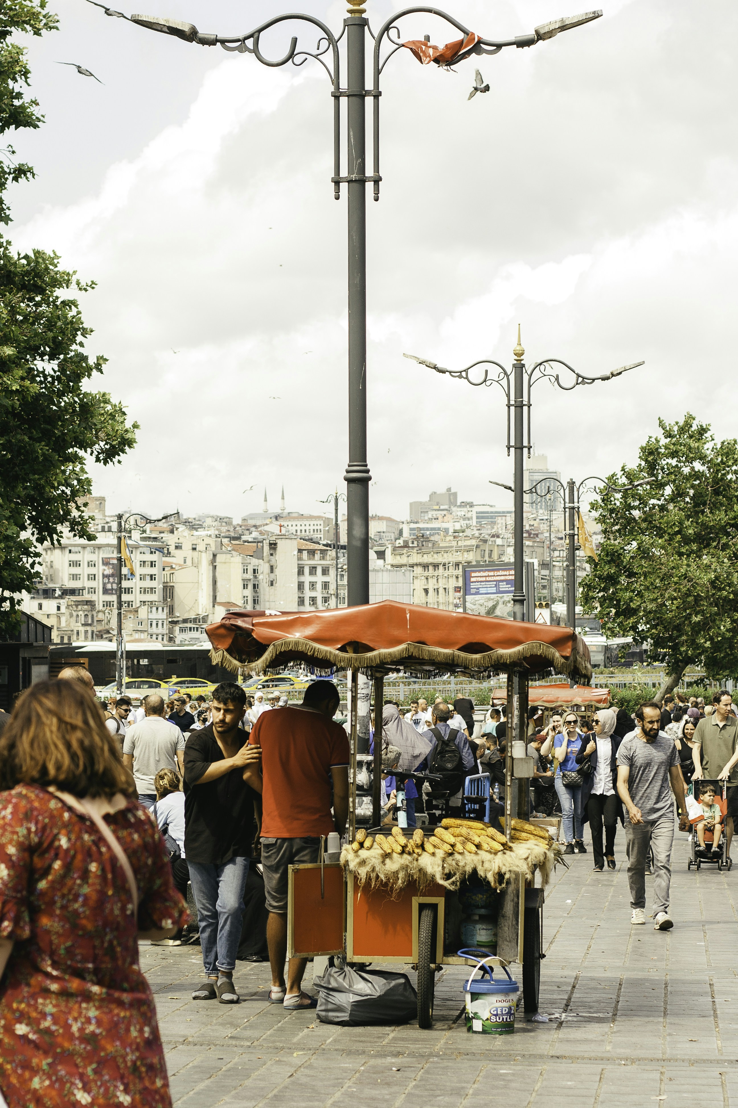 Crimson Canopy Corn Vendor Along a Sunlit Riverside Promenade
