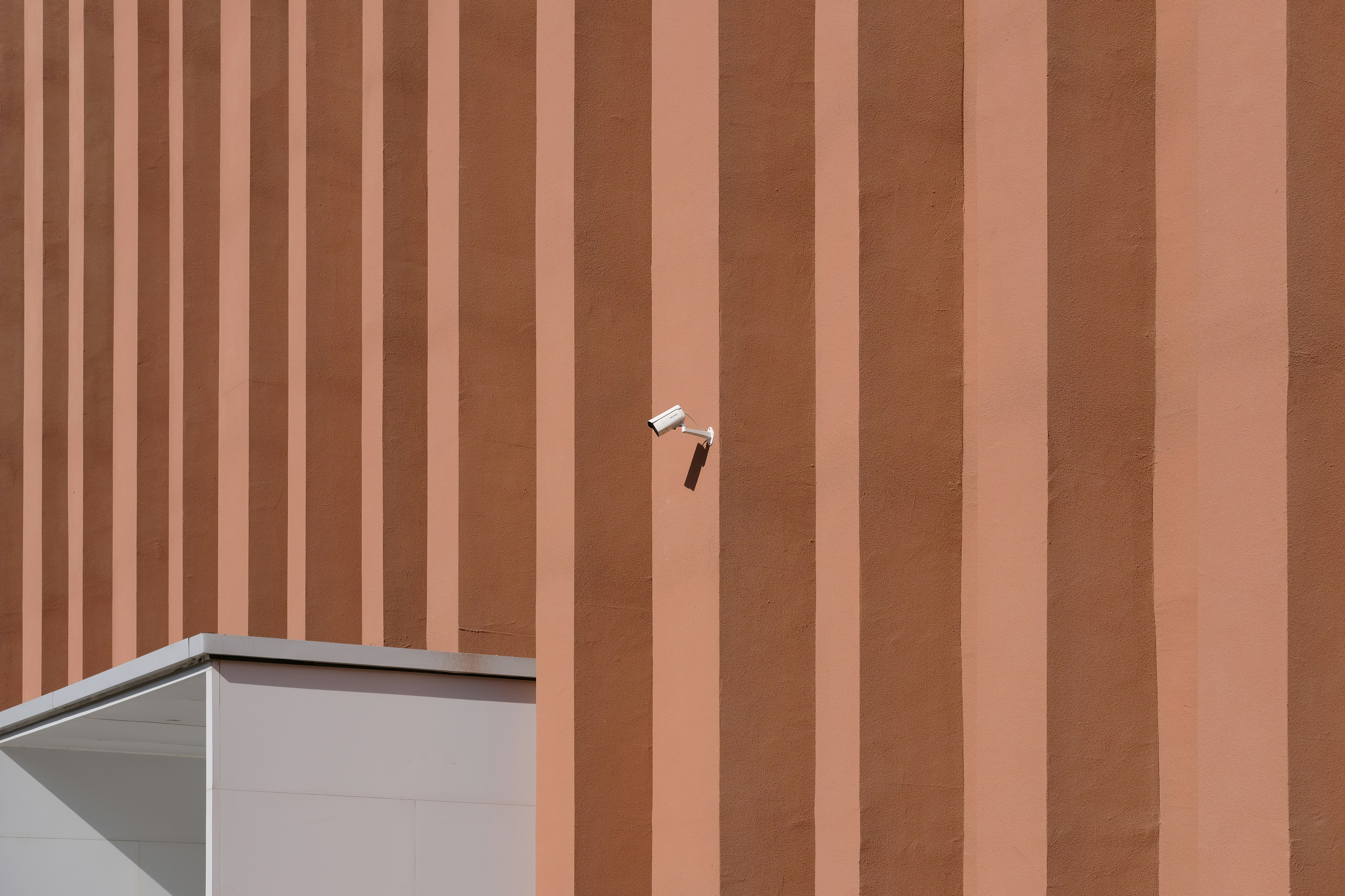 A Lone Camera Keeps Watch on a Striped Facade