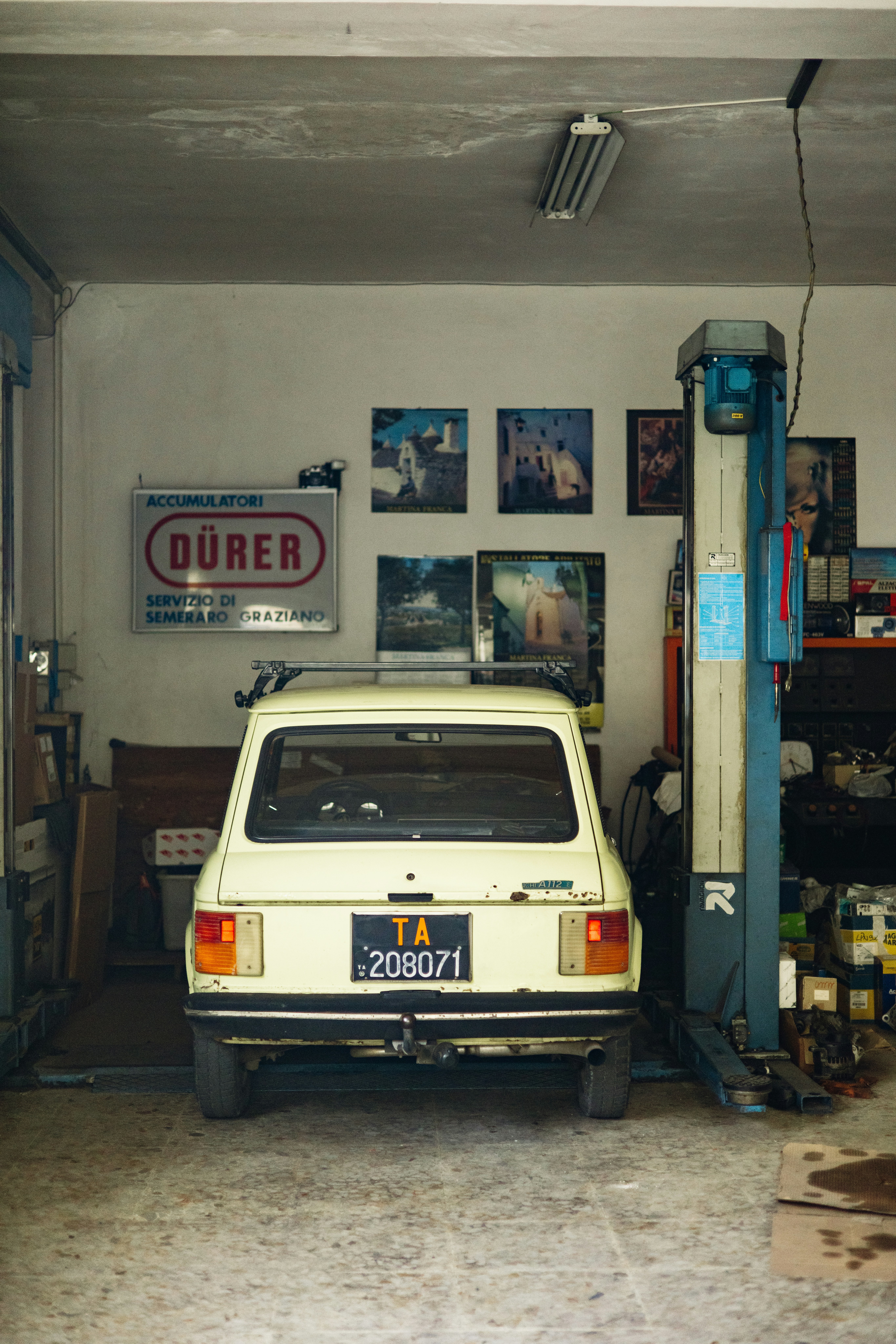 Rear View in a Quiet Italian Garage: A Vintage Hatchback Anchored by a Hydraulic Lift
