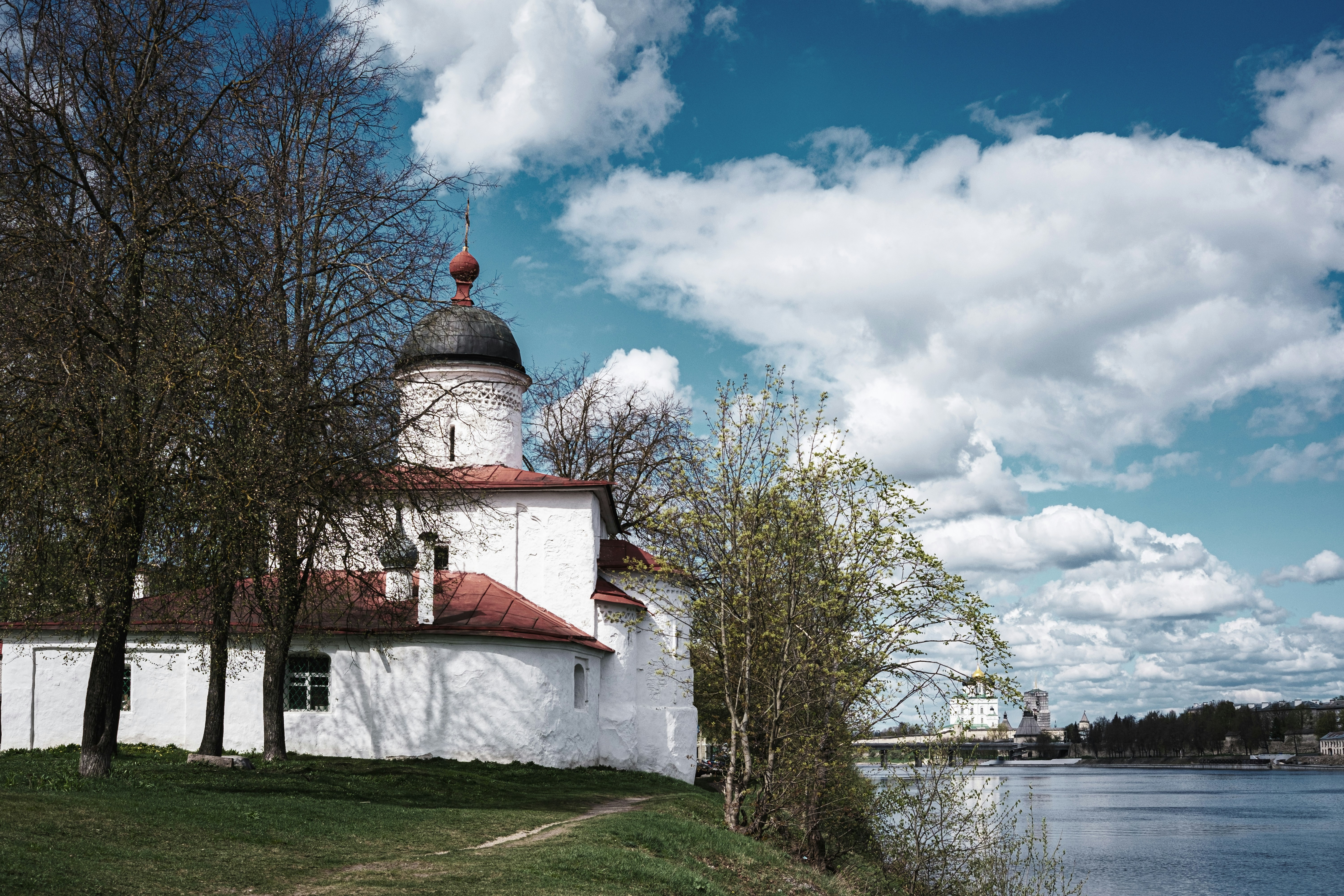 a white building with a red roof next to a body of water