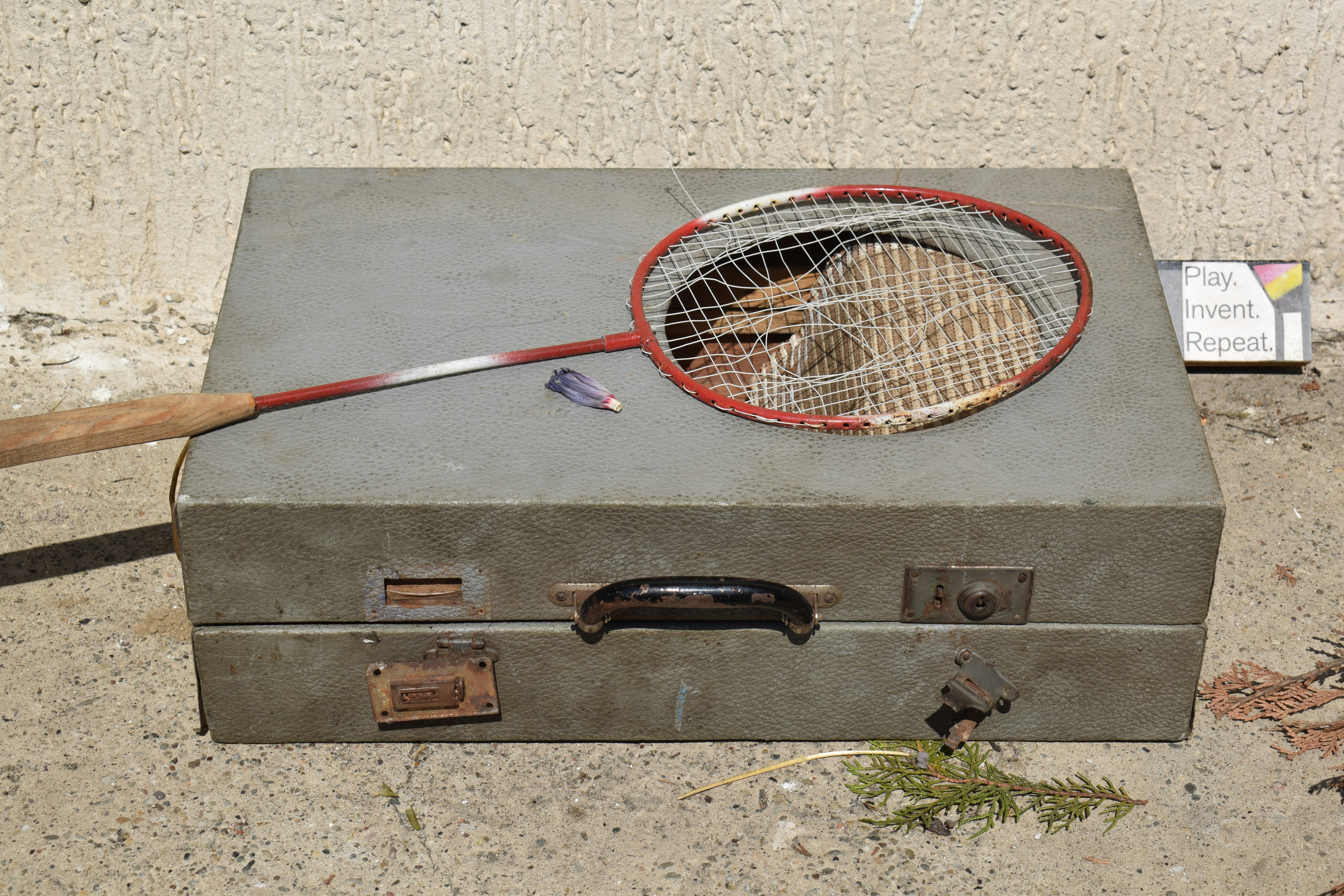 Old Courtship of Steel: A Tennis Racket Resting on a Weathered Vintage Case