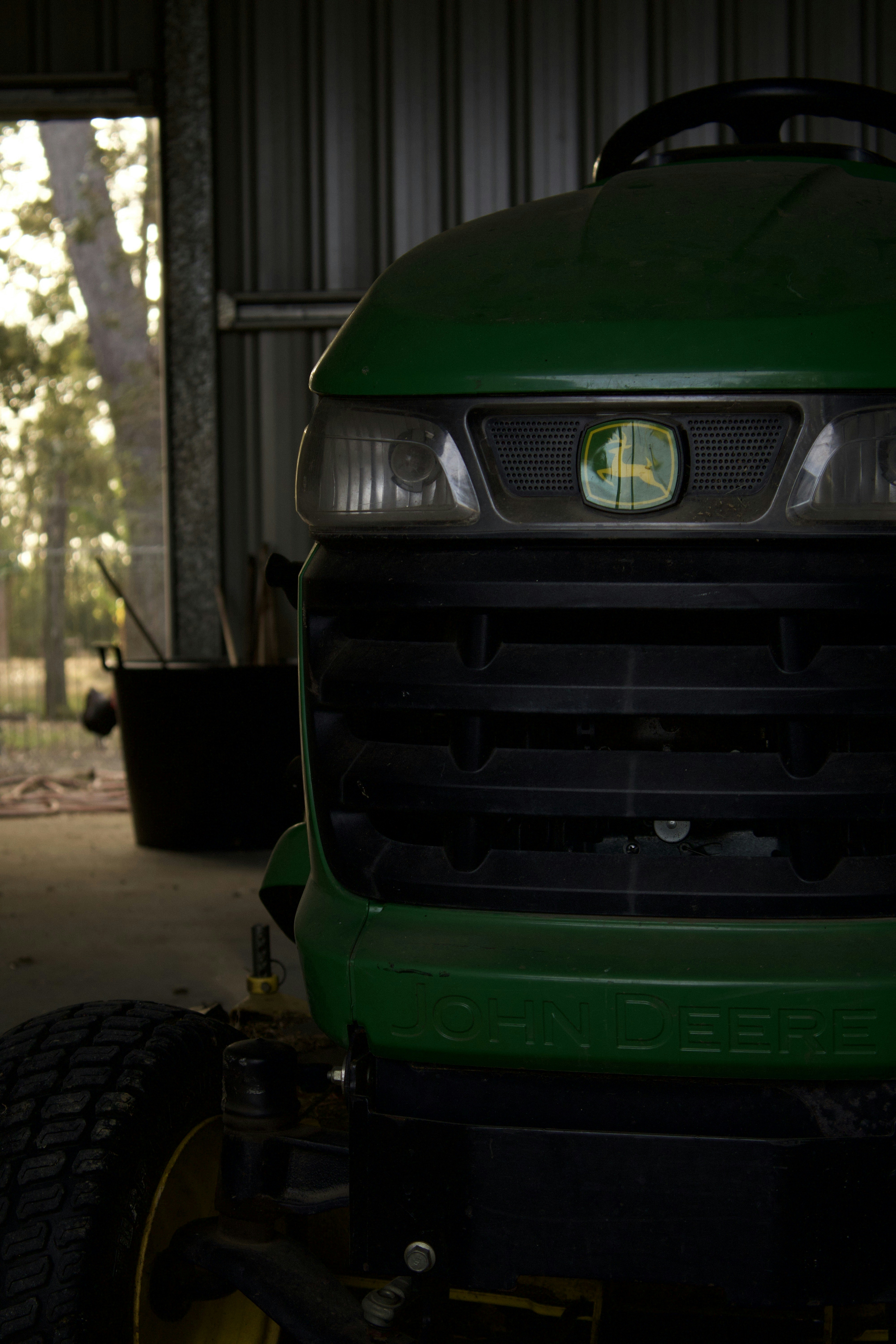 A green tractor parked inside of a garage photo – Free John deere Image ...