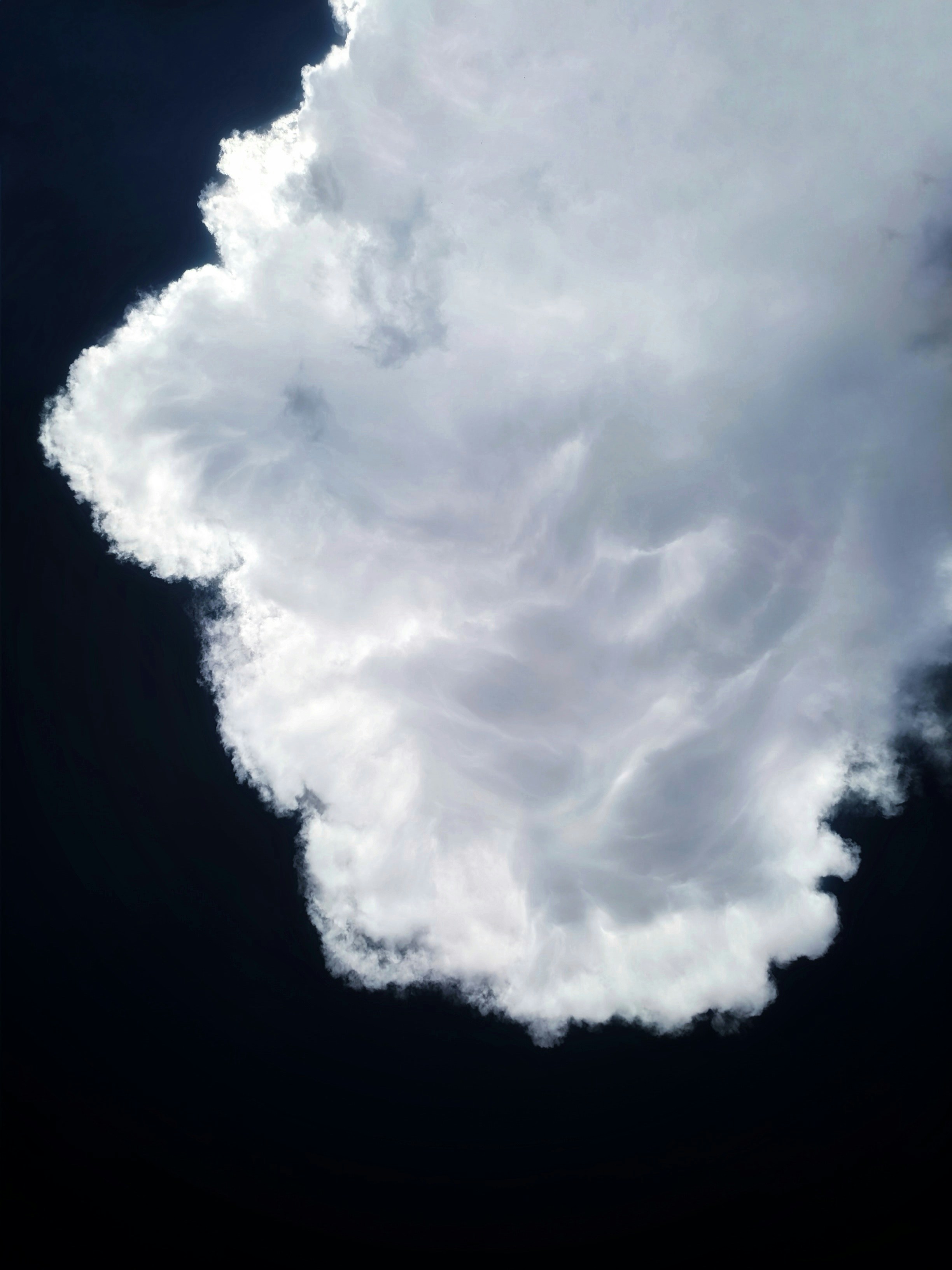 A single, bright cumulus dominates a dark sky, highlighting contrast and cloud texture.