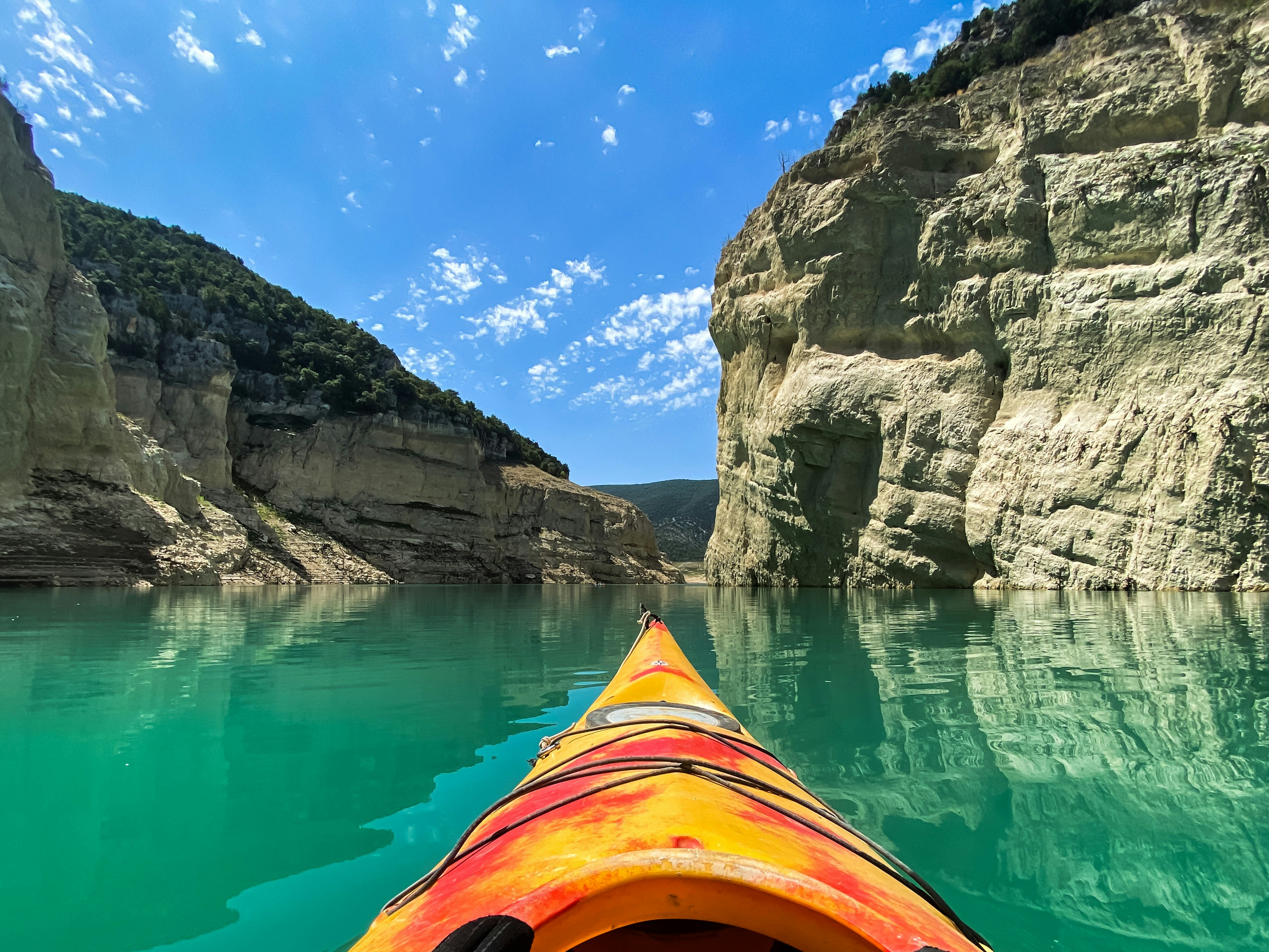 A kayak in the middle of a lake with cliffs in the background photo ...