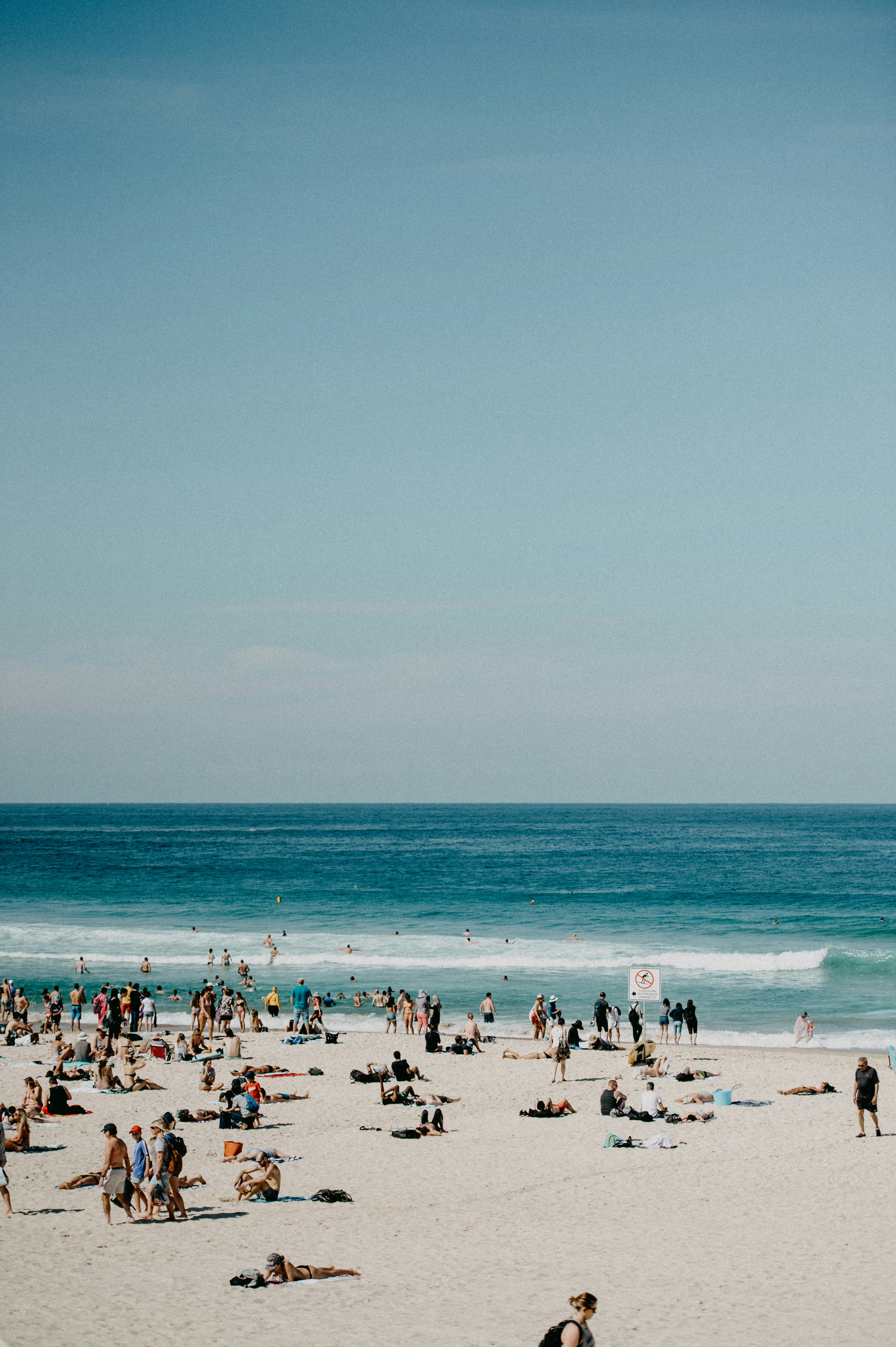 A crowded beach with people sitting and standing in the sand photo ...