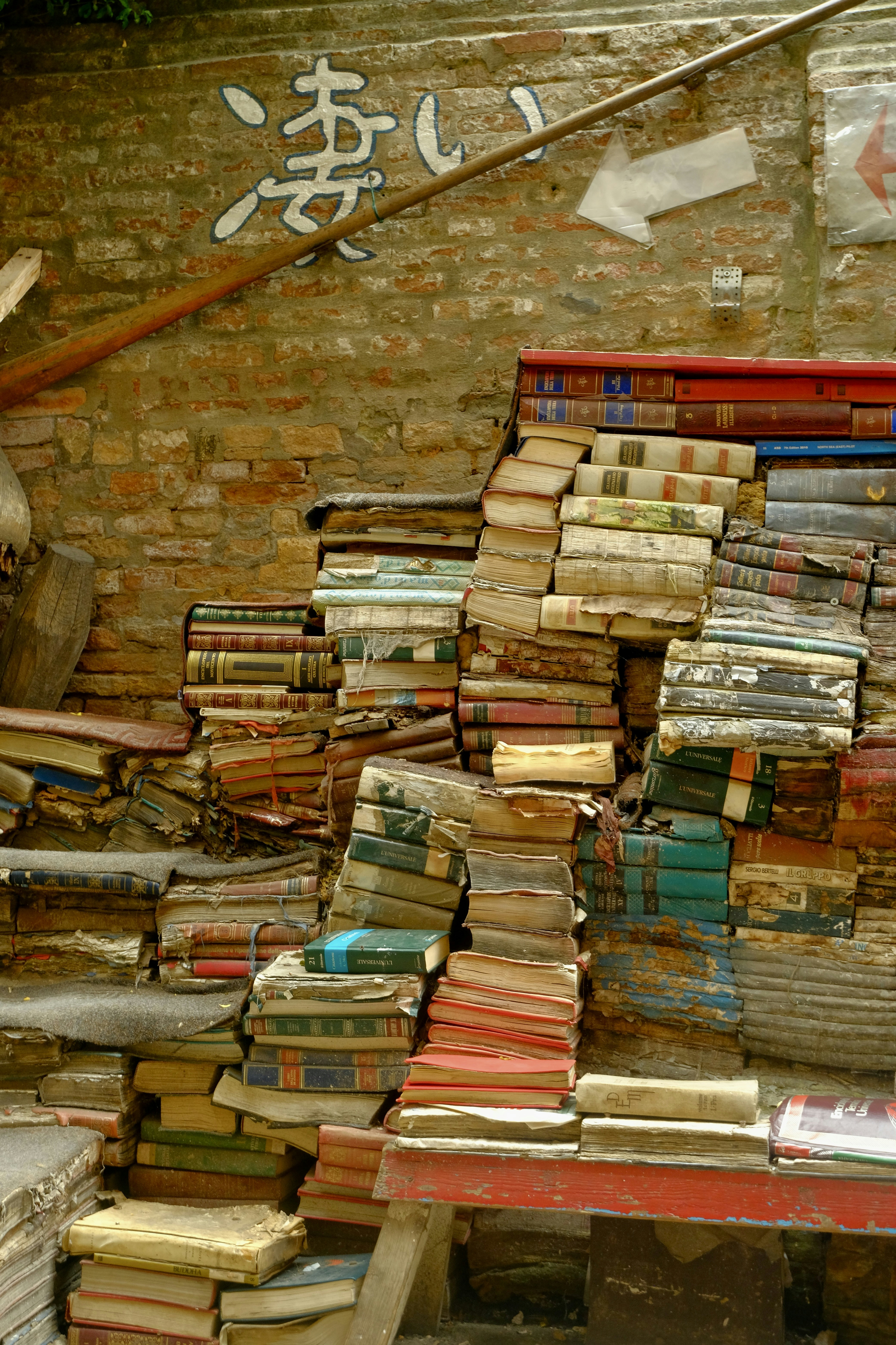Towers of Tattered Tomes Against a Weathered Brick Wall