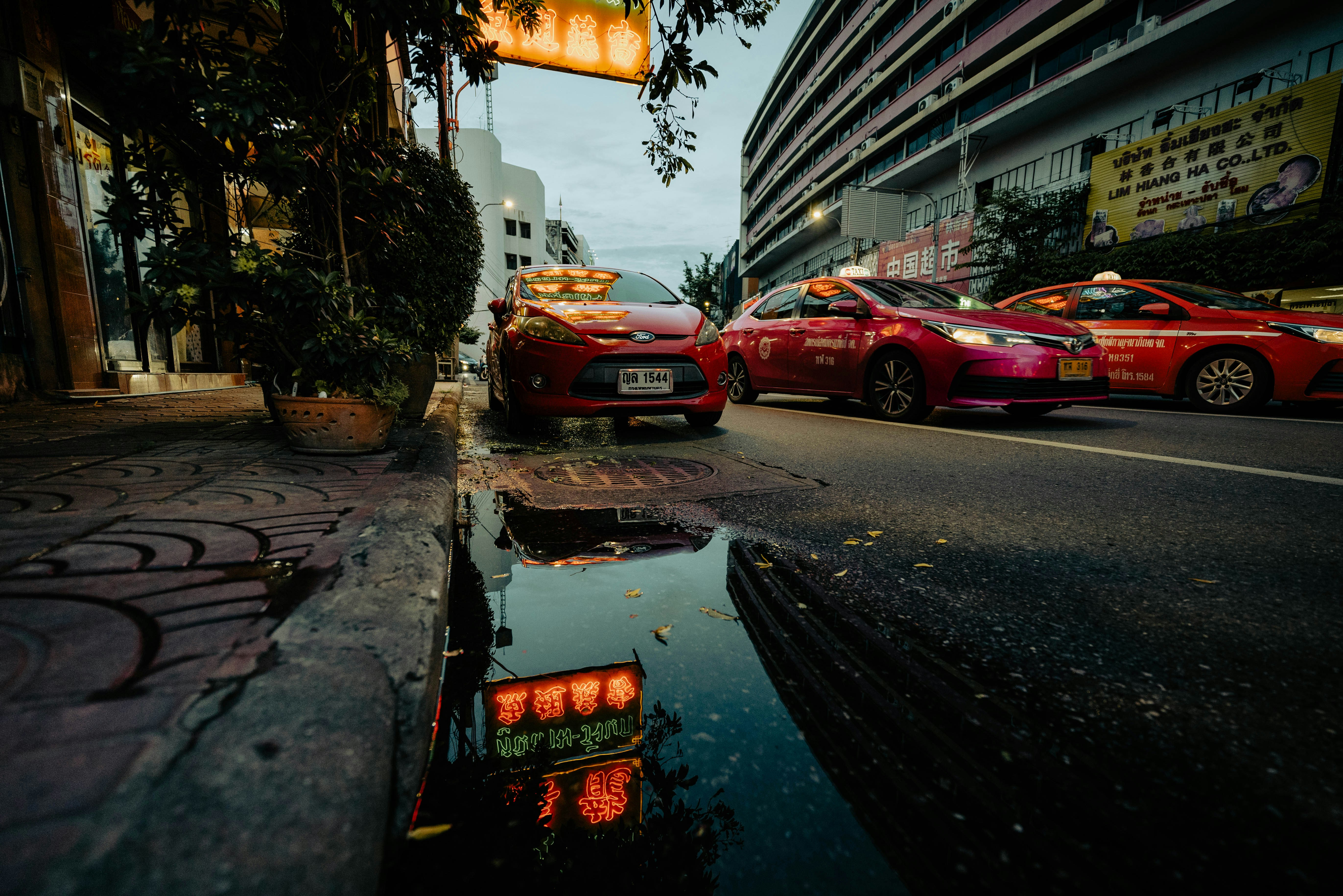 Puddle Reflections and Red Cabs on a Neon-Soaked Street