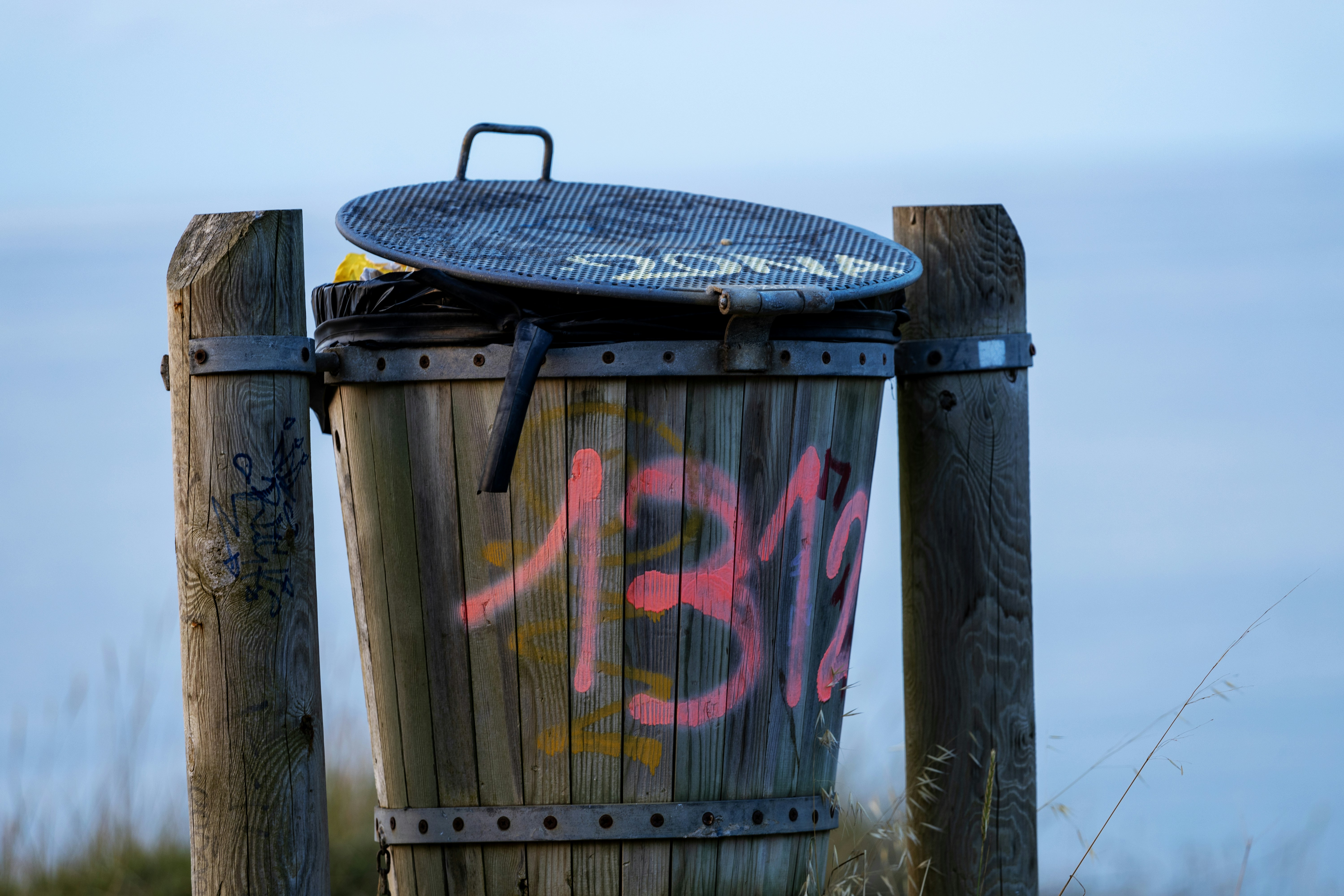 Neon Graffiti on a Weathered Seaside Trash Can