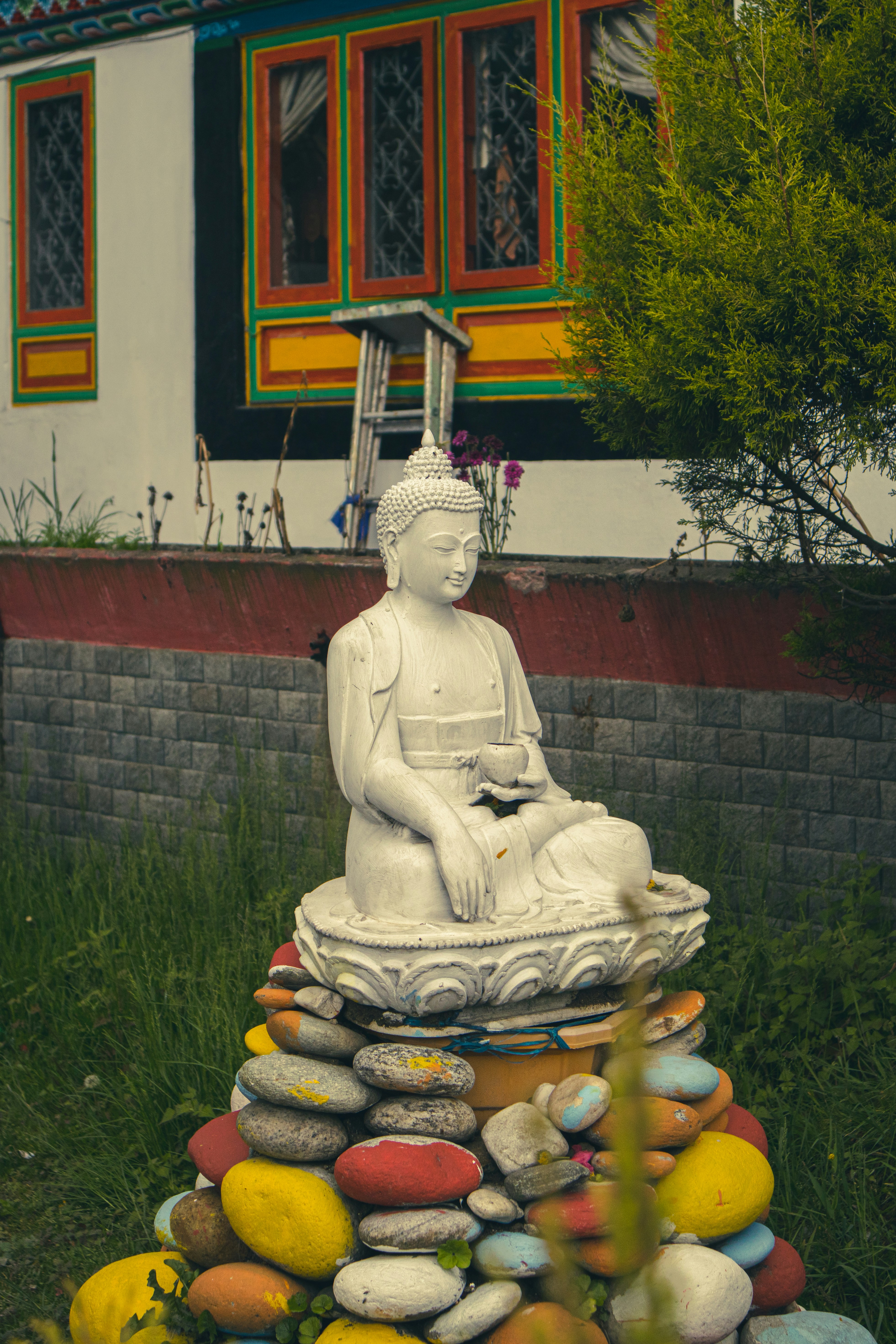 Buddha Beneath Painted Windows: Tranquil Statue Over a Palette of Stones