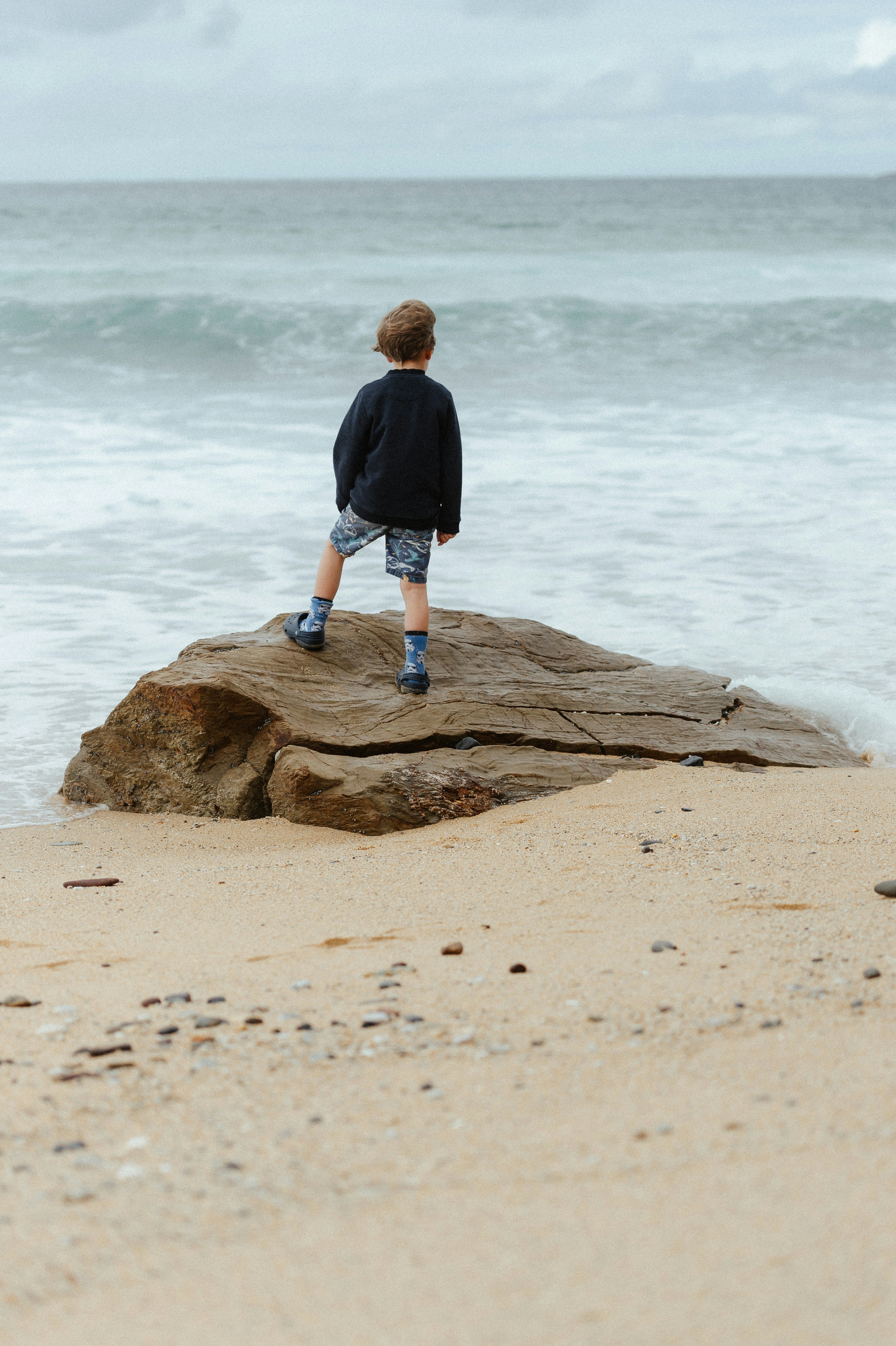 A young boy standing on a rock at the beach photo – Free Summer hols ...