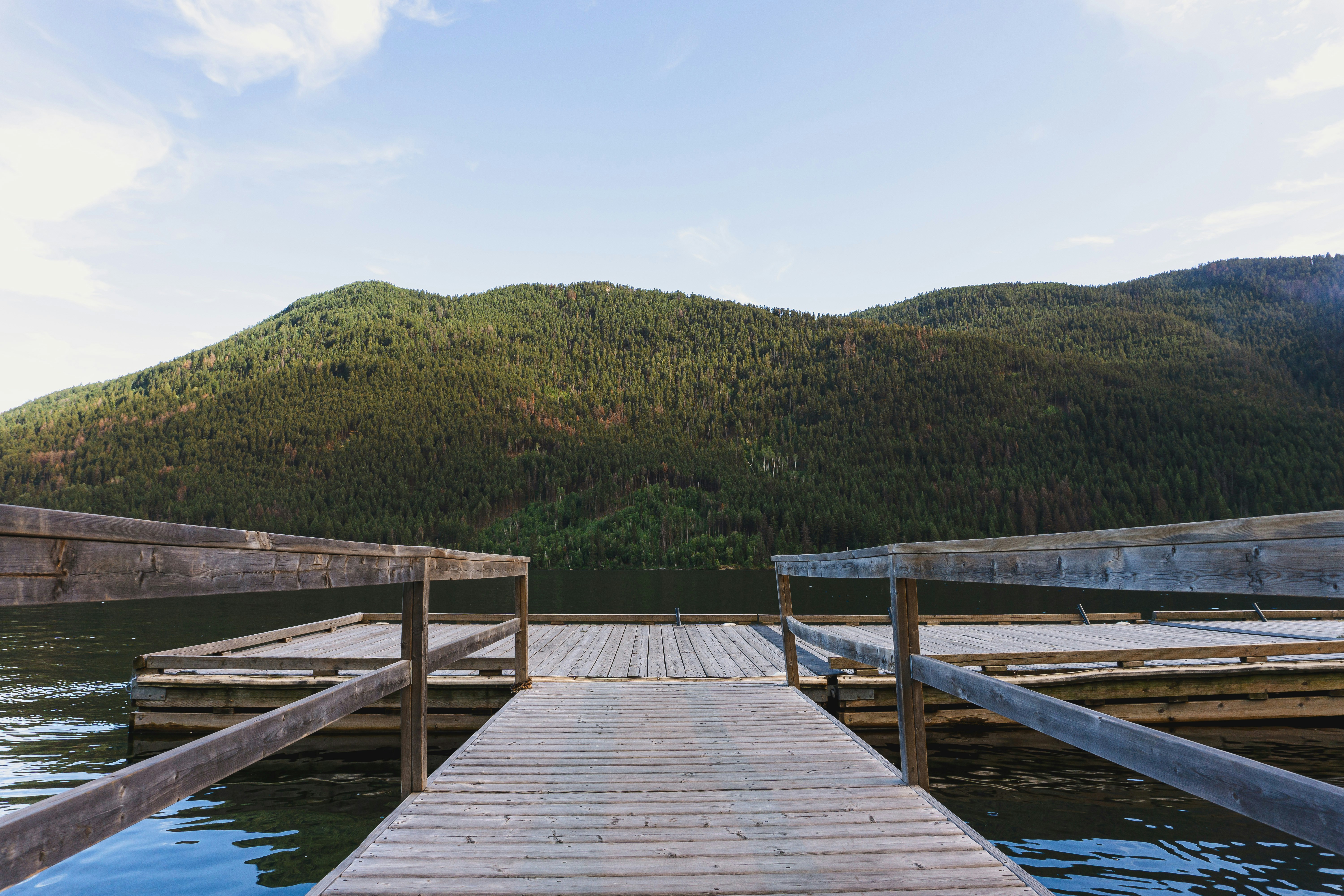A wooden dock with a mountain in the background photo – Free Trees ...