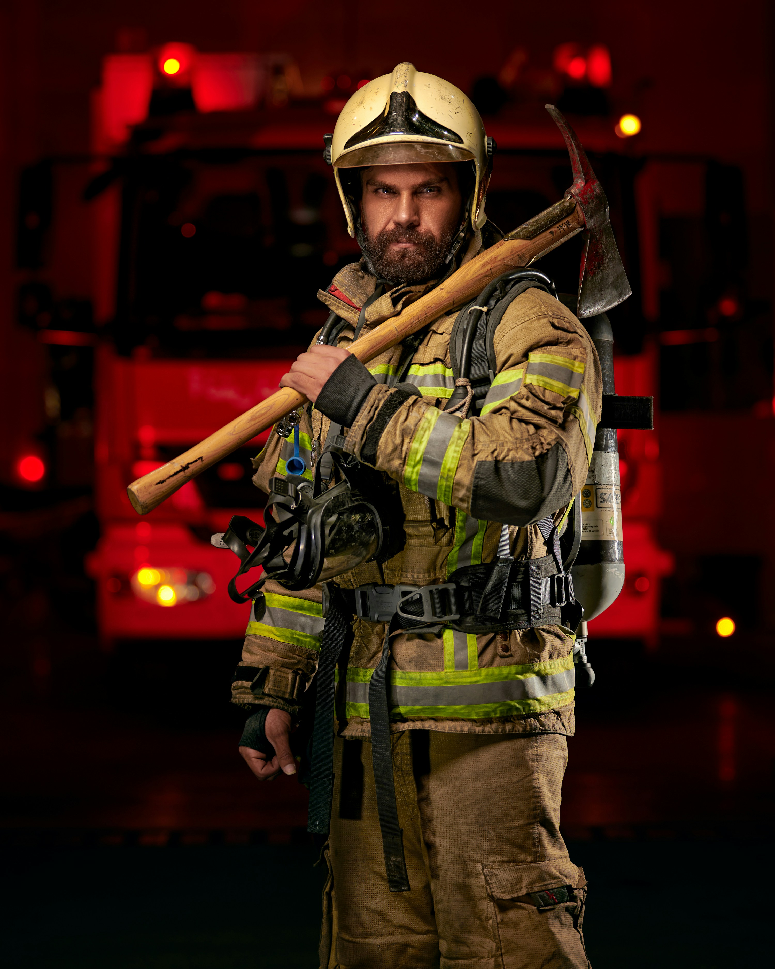 A firefighter holding a large axe in front of a fire truck photo – Free ...