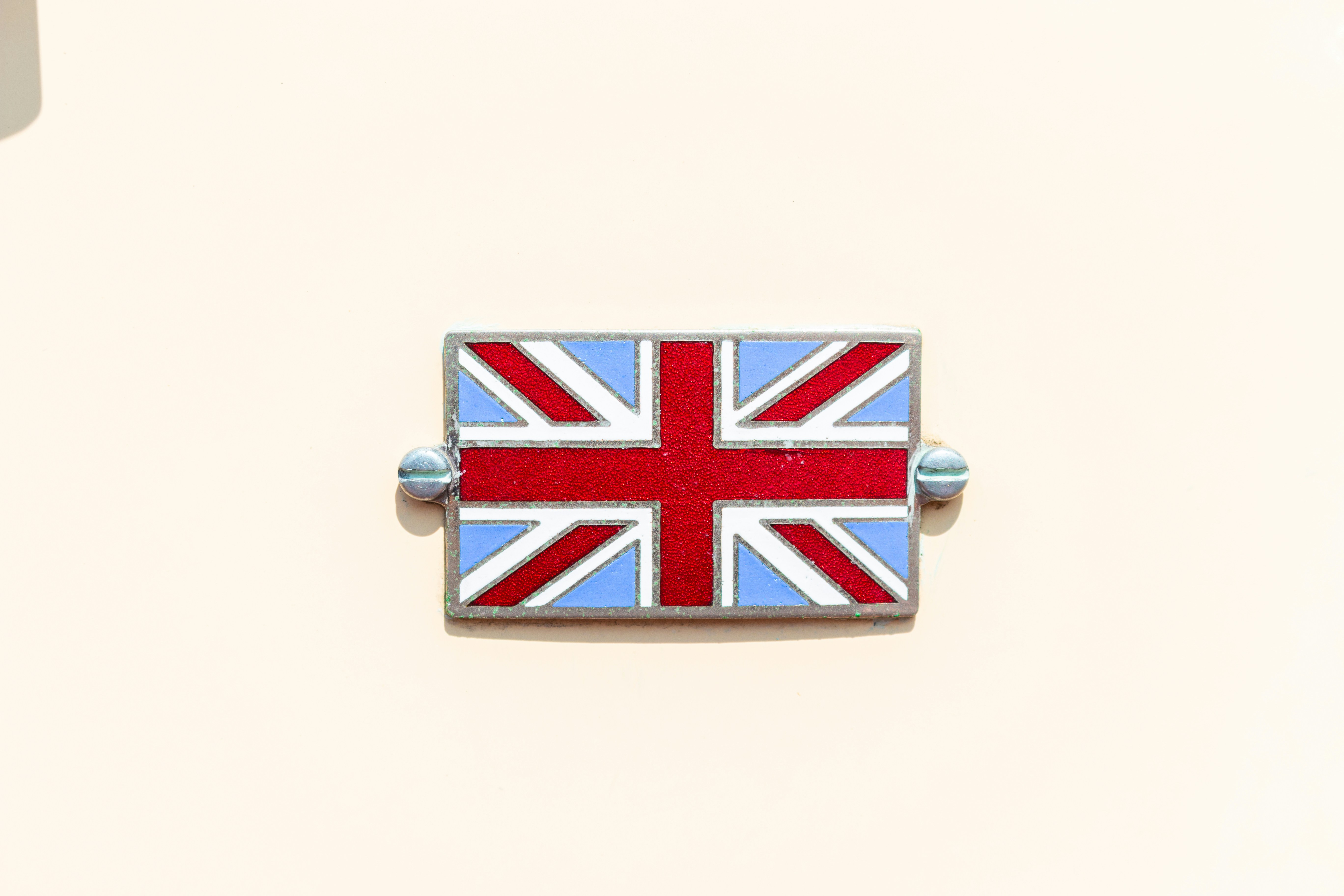 A british flag pin sitting on top of a white wall photo – Free On Image ...