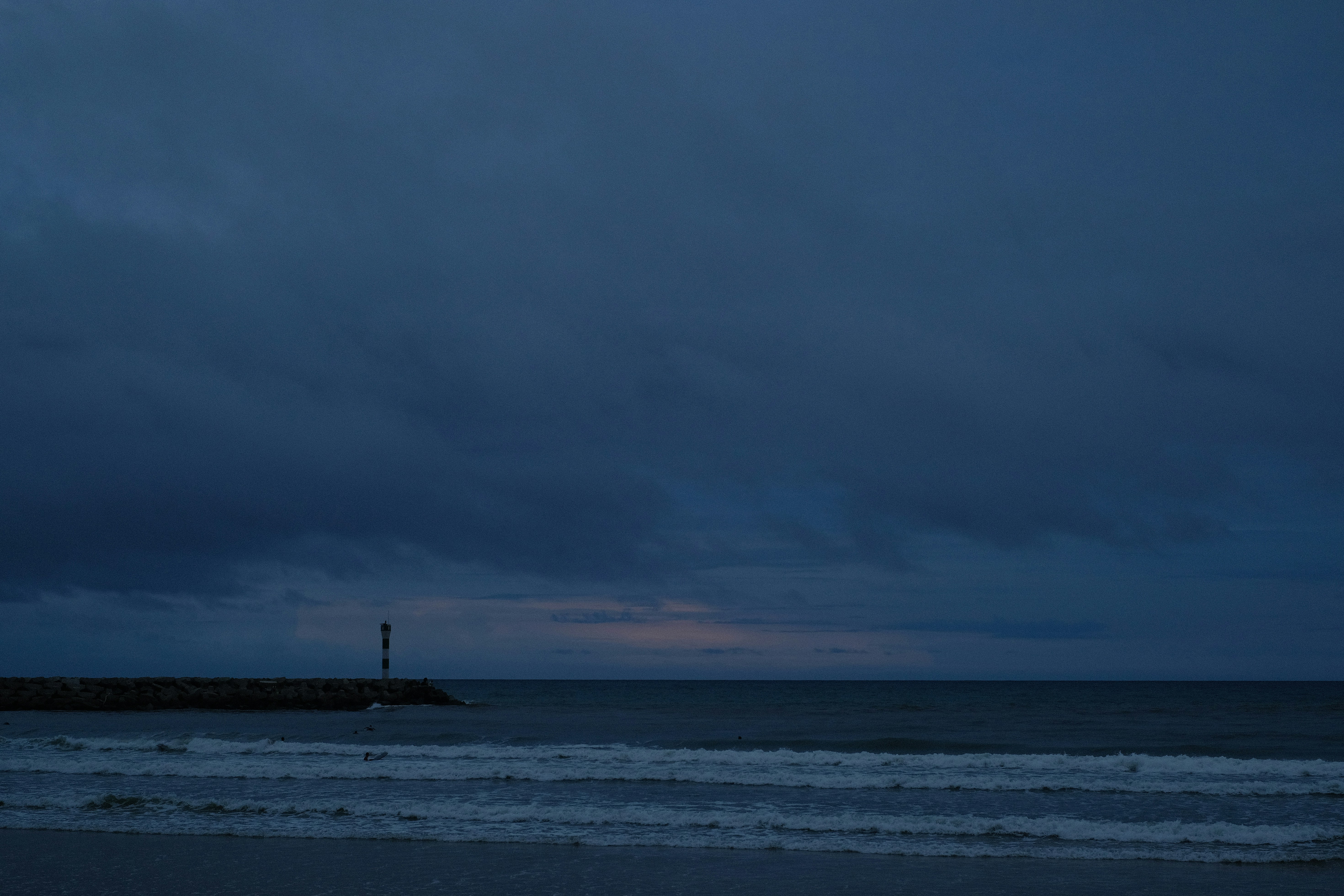 Coastal Horizon at Dusk: Lone Breakwater Spearheading Quiet Waves