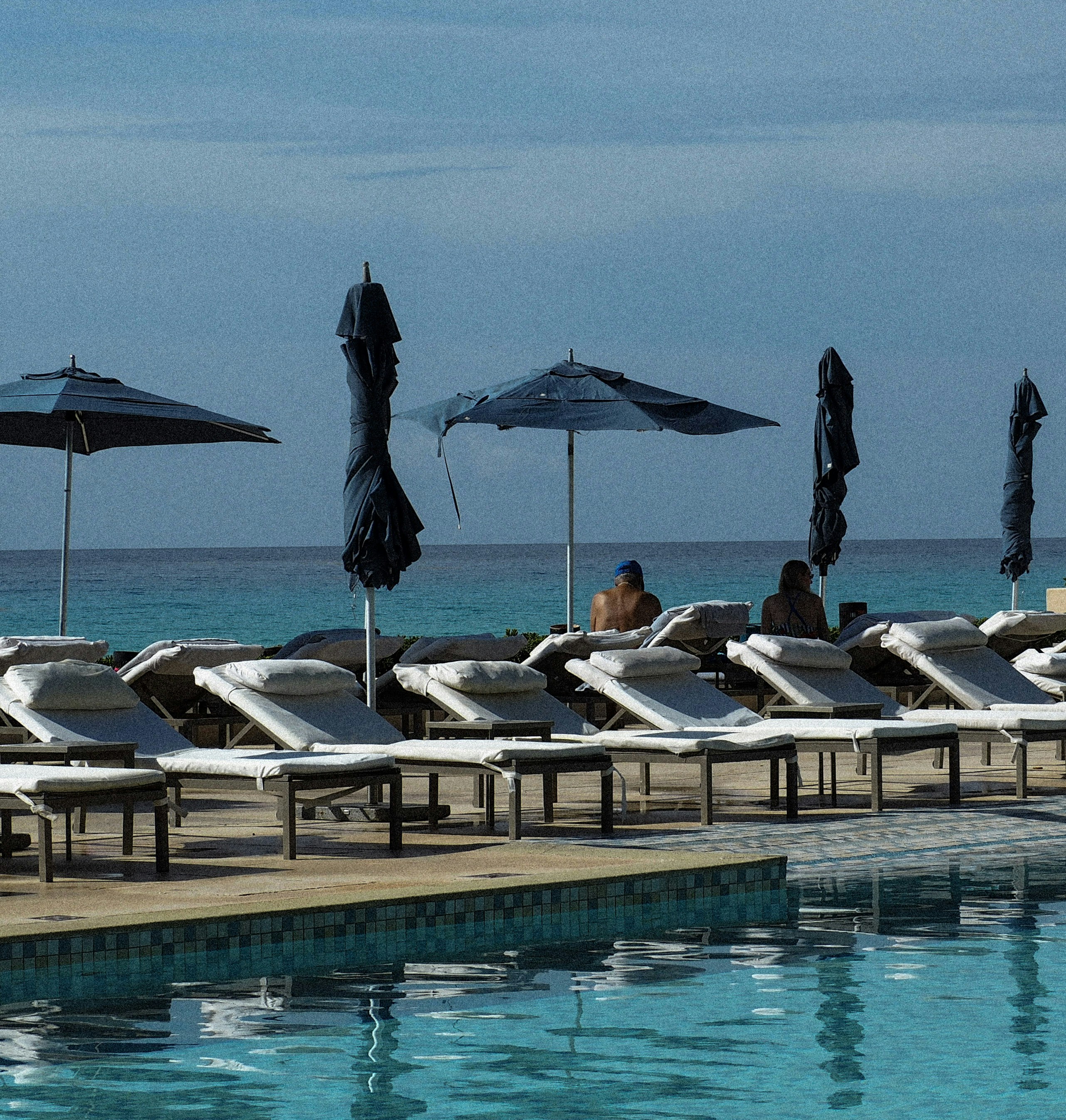 A row of lounge chairs sitting next to a swimming pool photo – Free ...