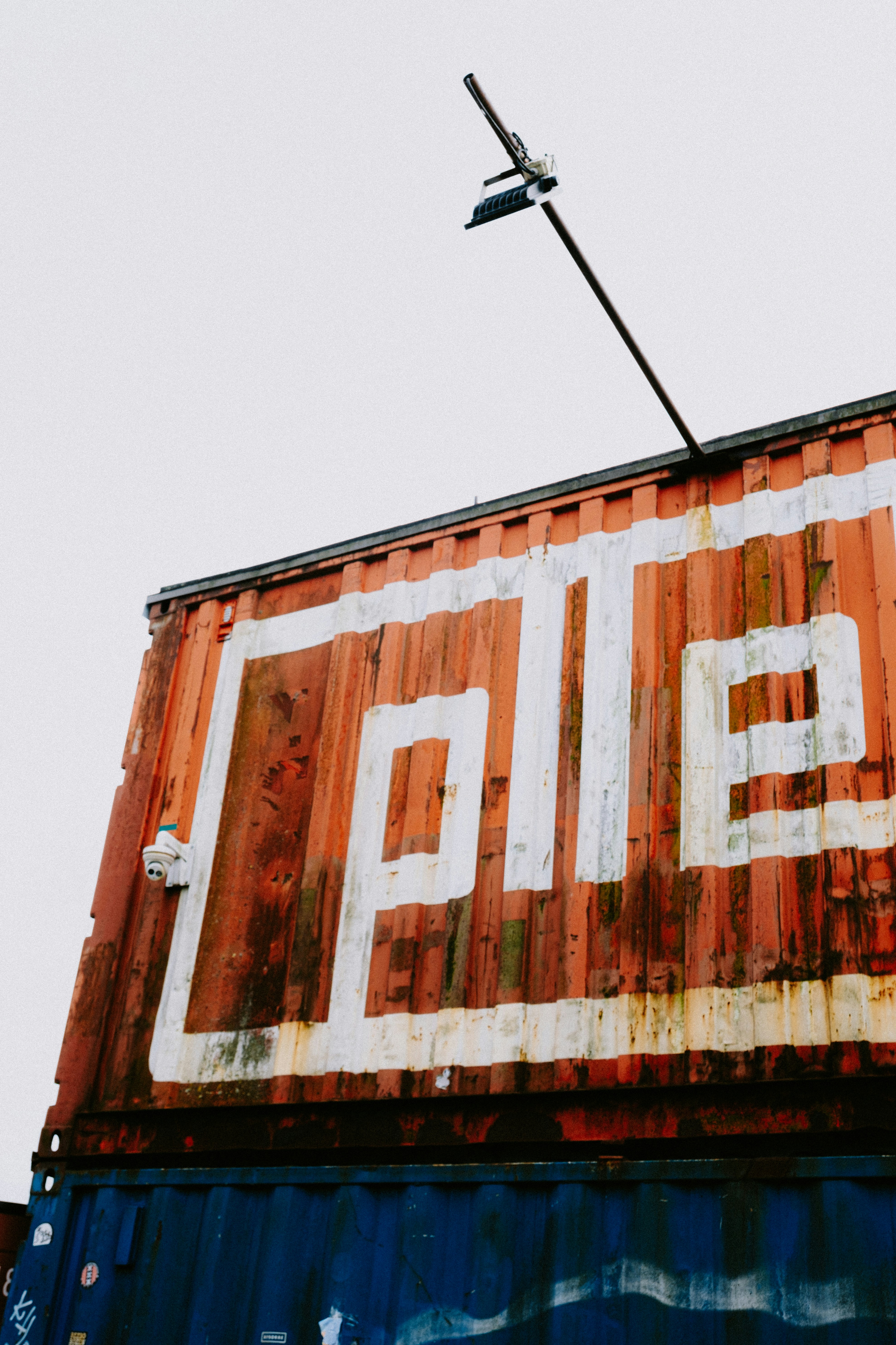 Open Above Rust: A Weathered Container Under a Slanted Mast