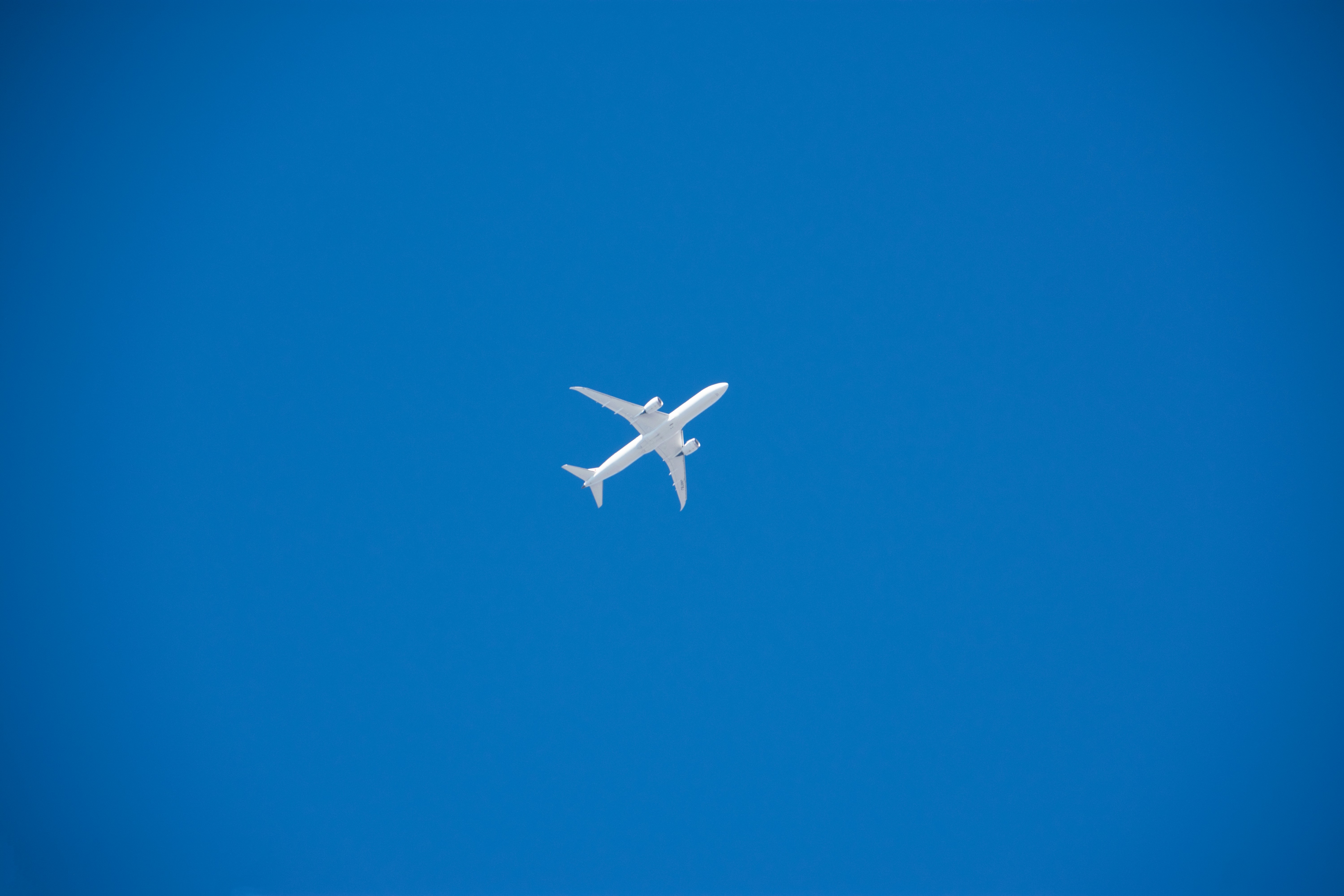 A commercial airplane gliding gracefully against a clear blue sky.
