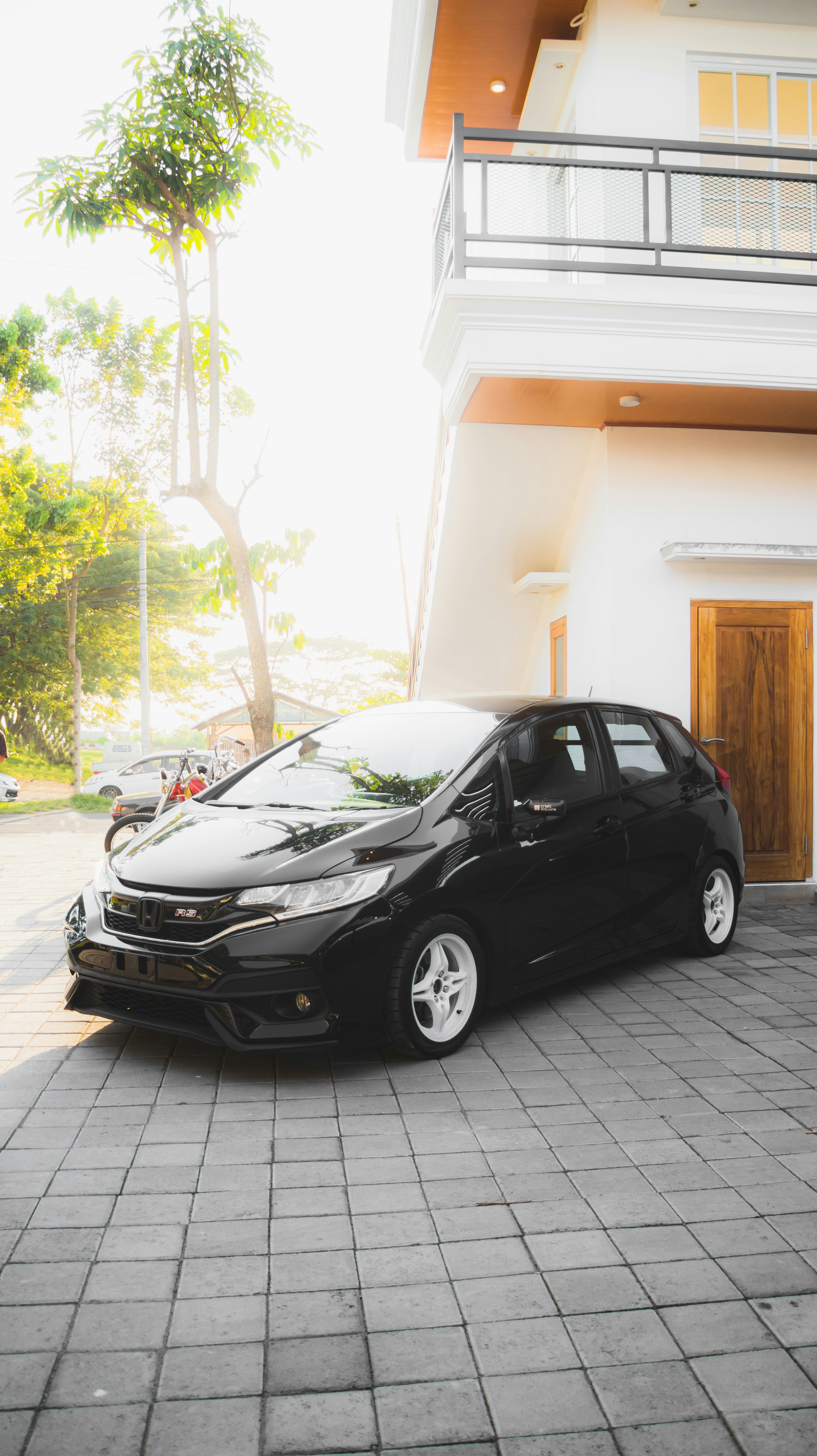 Sunlit Driveway Stance: A Sleek Black Hatchback by a Modern Villa