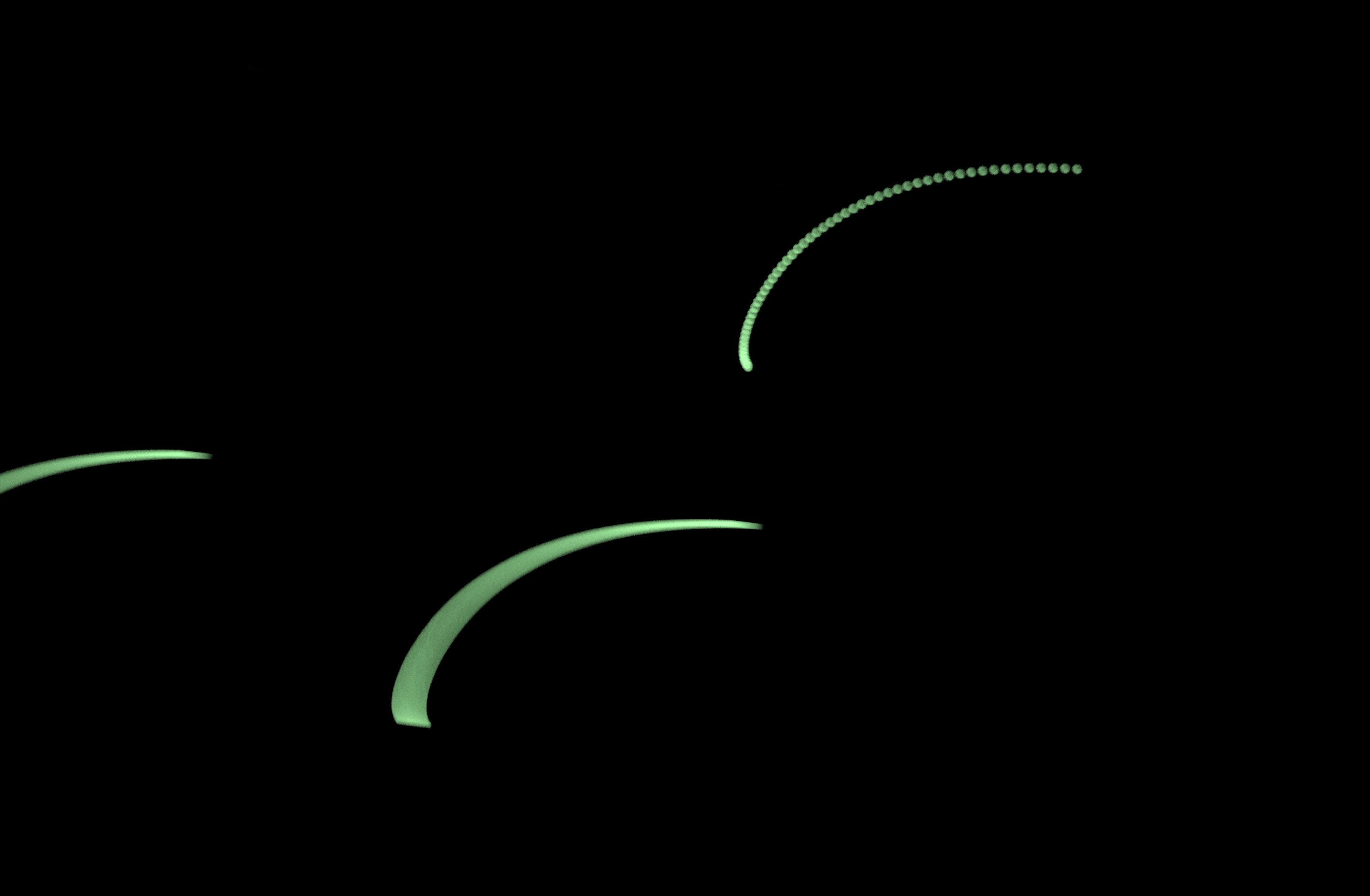 Trio of Mint-Glow Arcs Drift Across Black