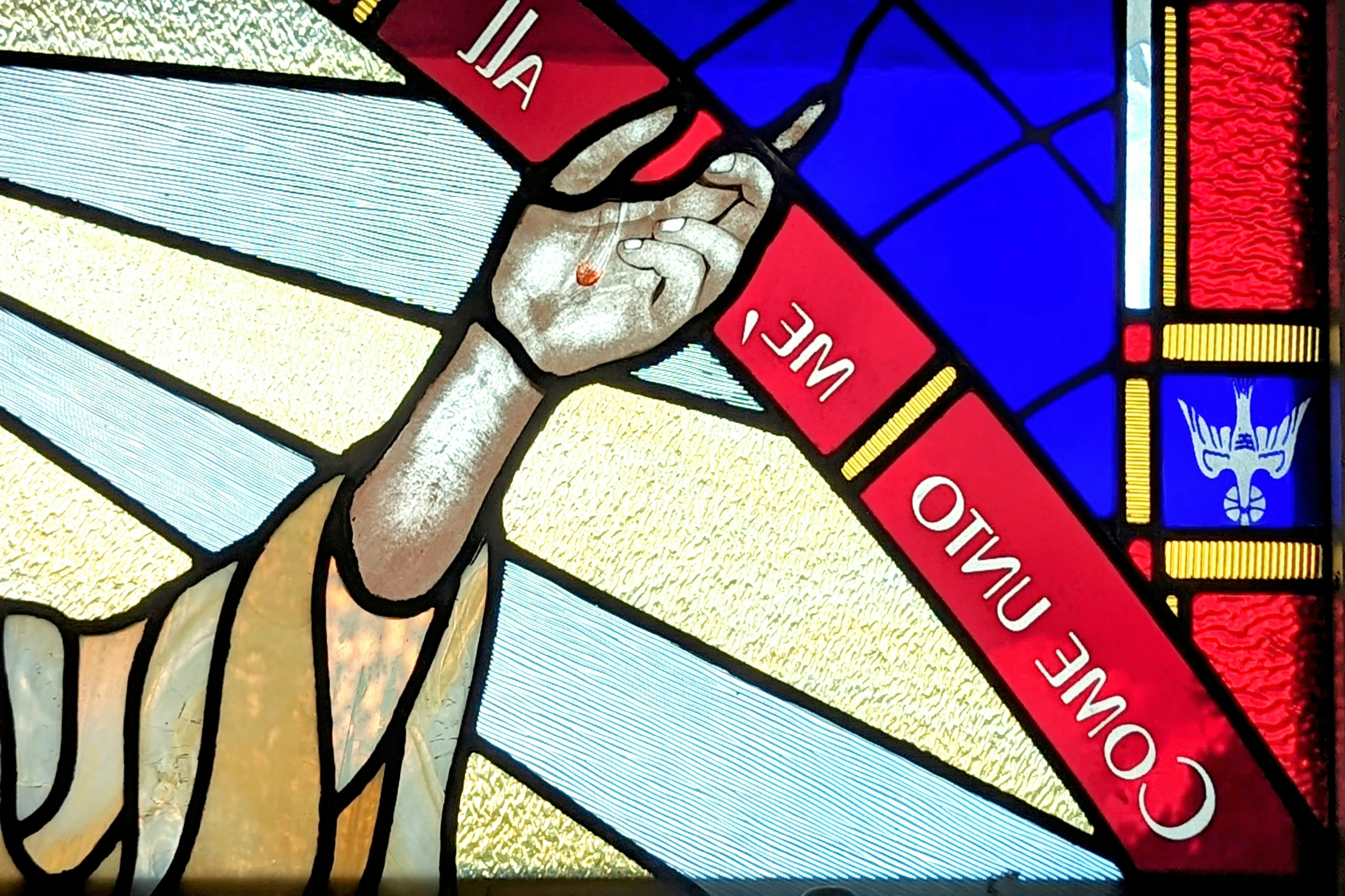 A stained glass window with a hand holding a pen photo – Free ...
