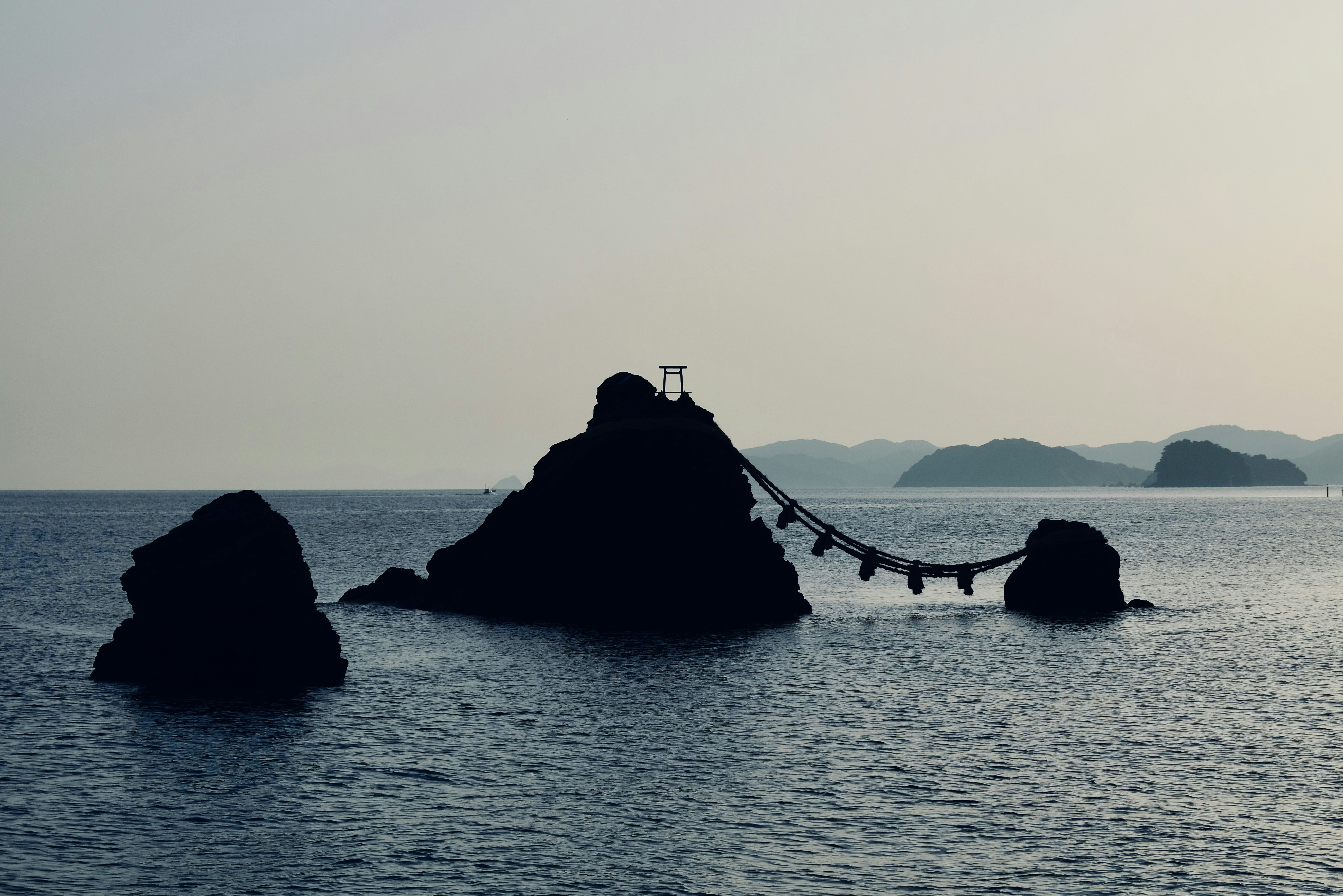 Dusk Silhouette: The Sacred Rope Bridge Between Sea Rocks