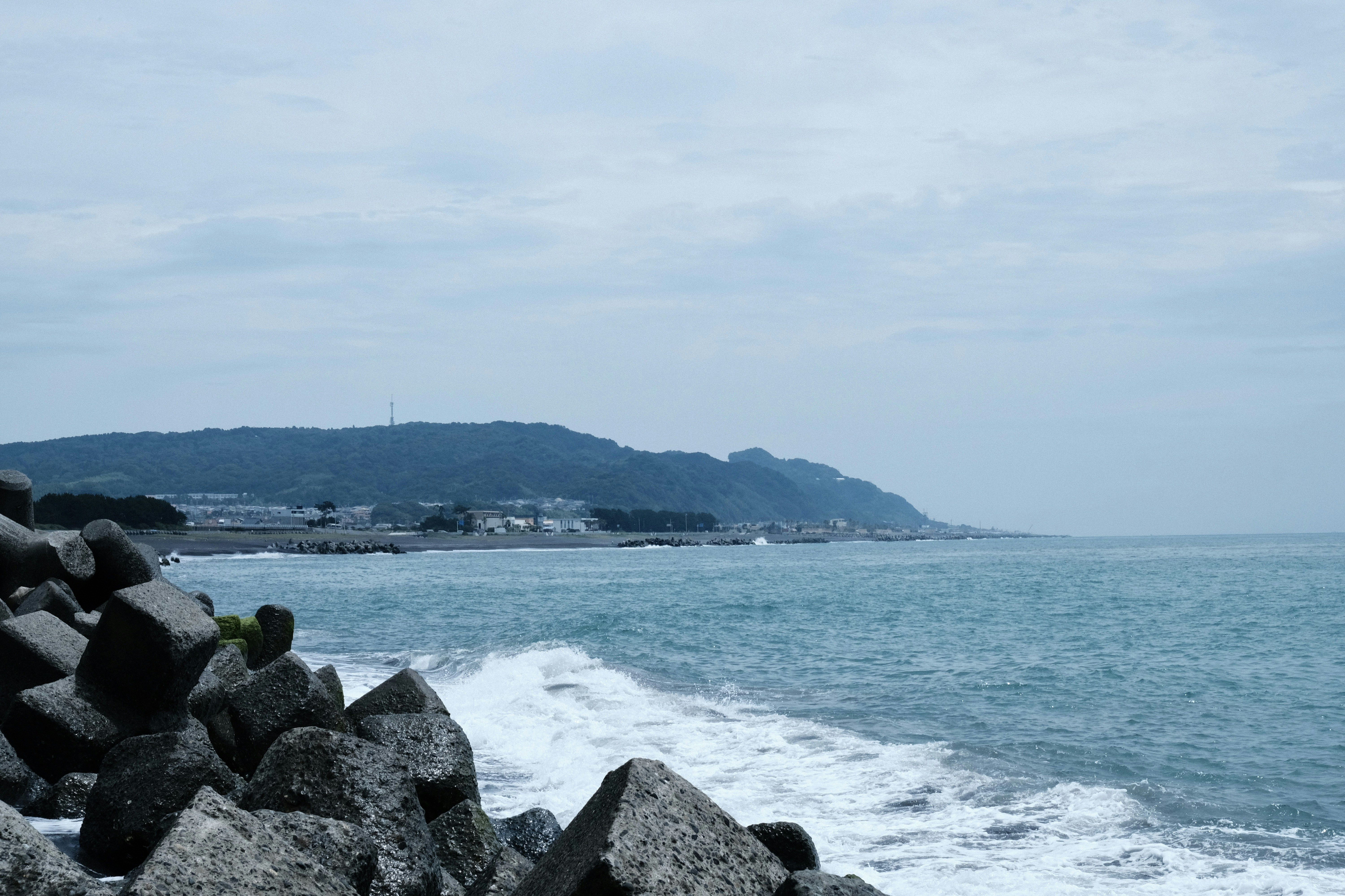 Rocks at the Edge: A Calm Sea Meets a Distant Ridge