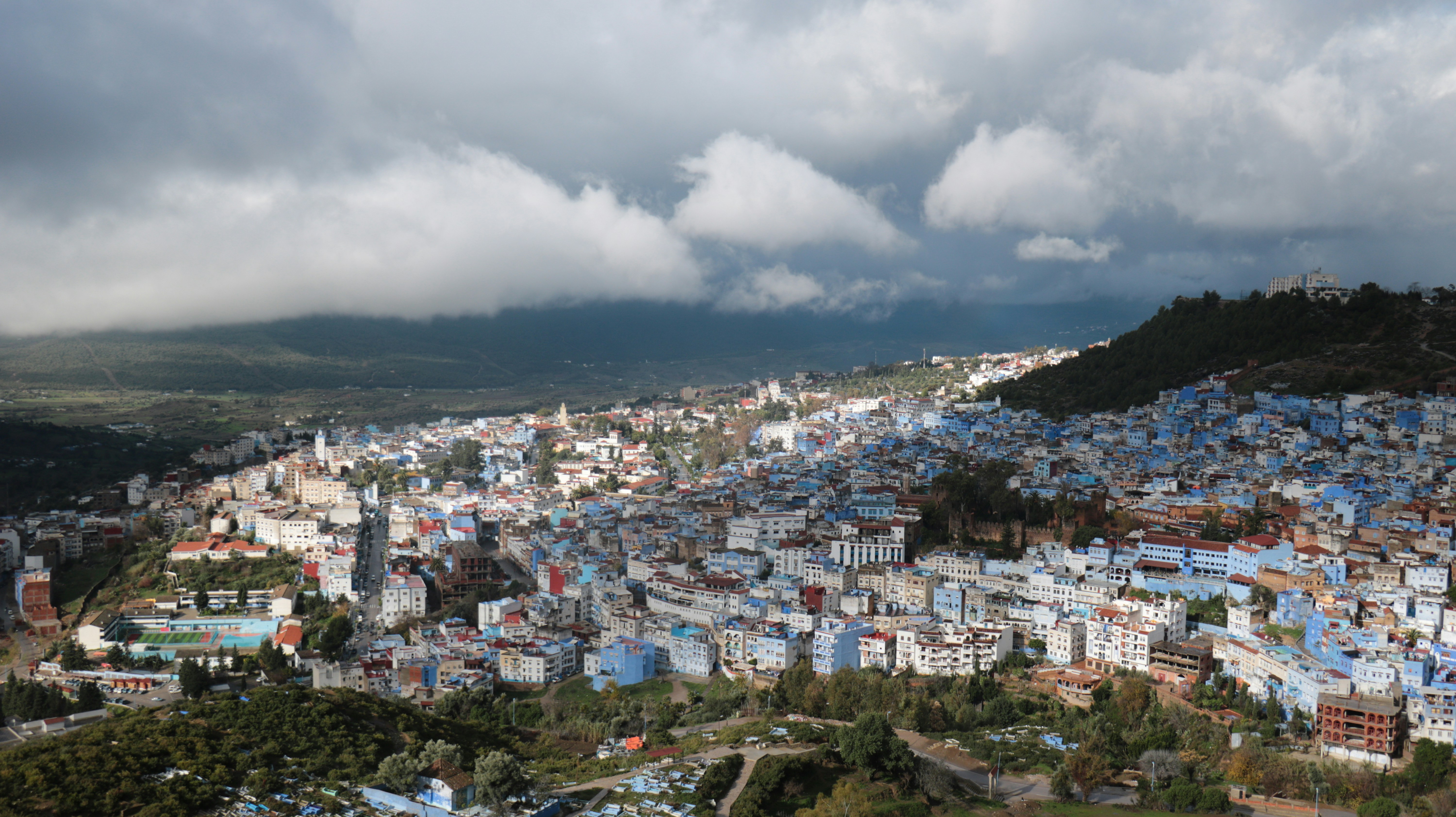 Azure Hillside: A cobalt-roofed town unfolds along the slope beneath dramatic skies