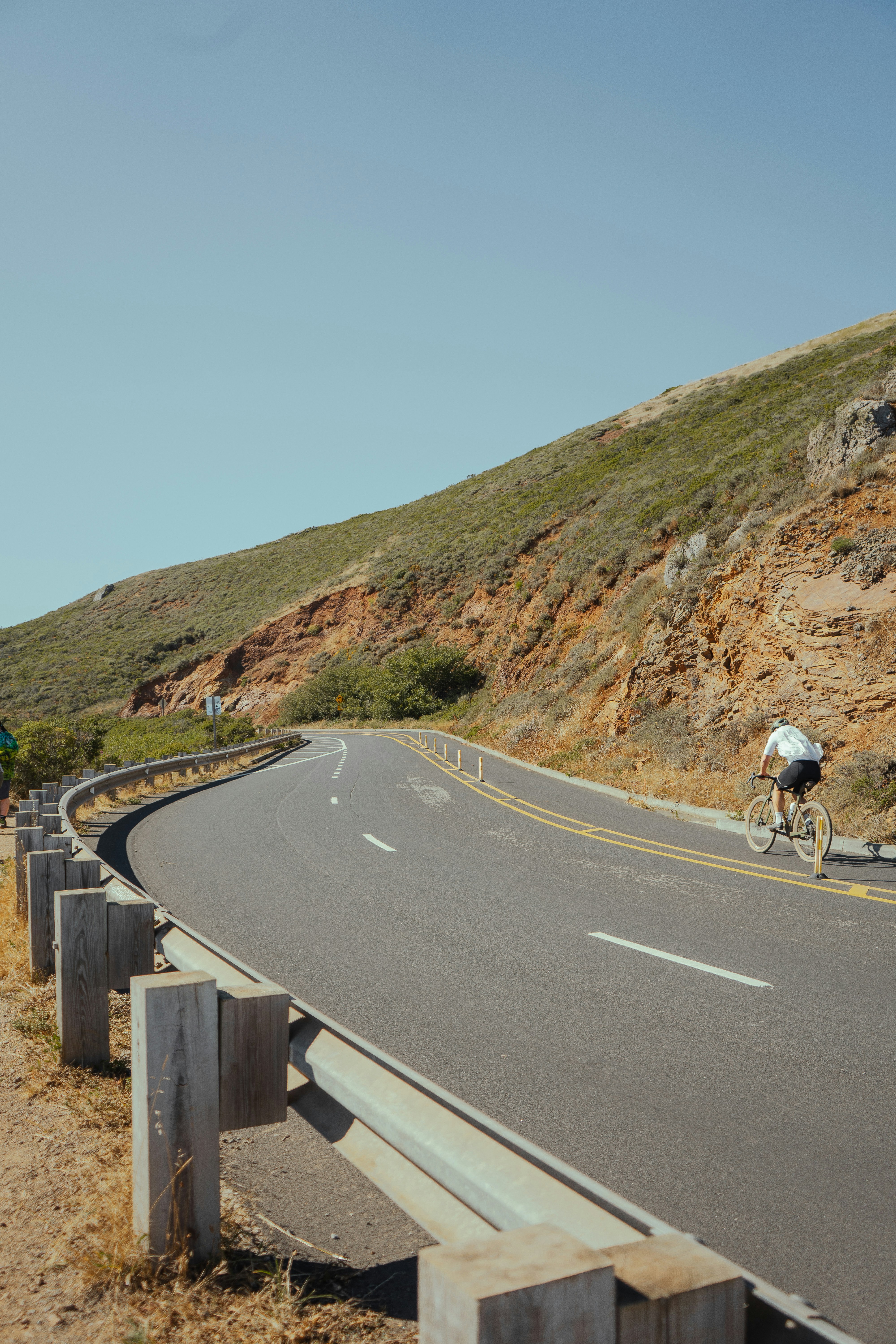 Coastal Curve: Cyclist on a Sunlit Cliffside Road