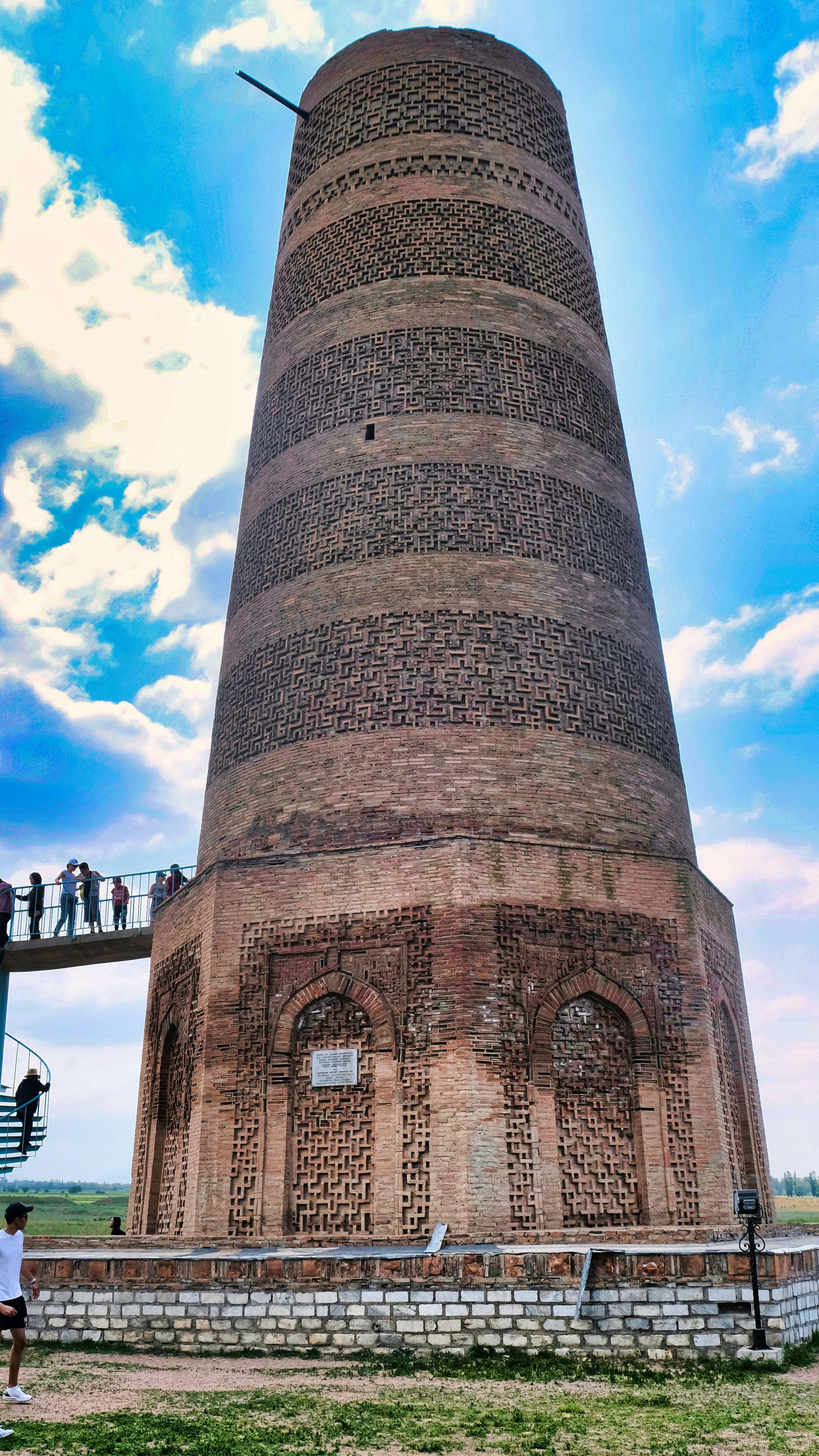 Brick Colossus Under Sky: A Cylindrical Tower with a Suspended Walkway