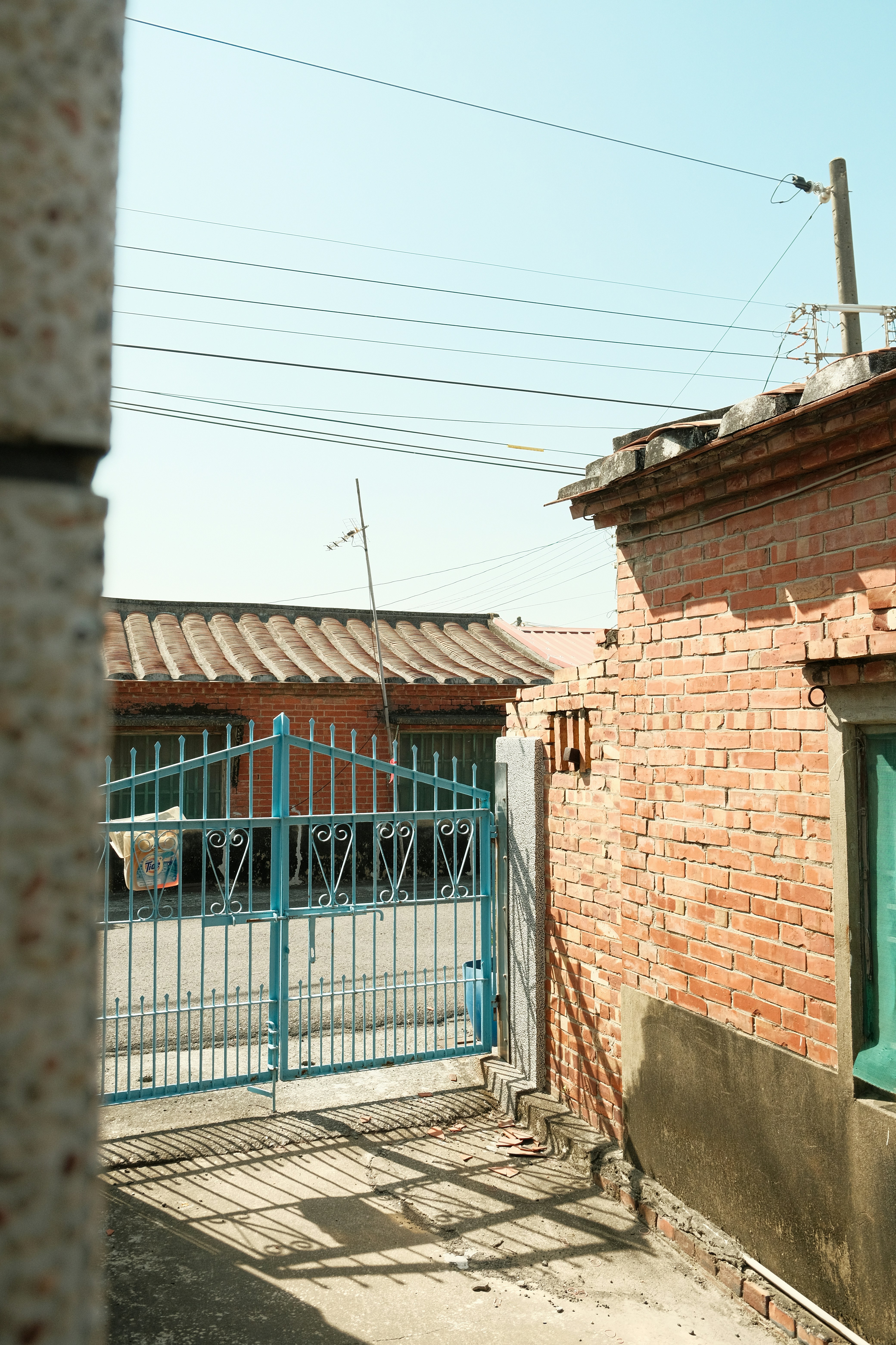 Blue Gate Framing a Sunlit Brick Alley