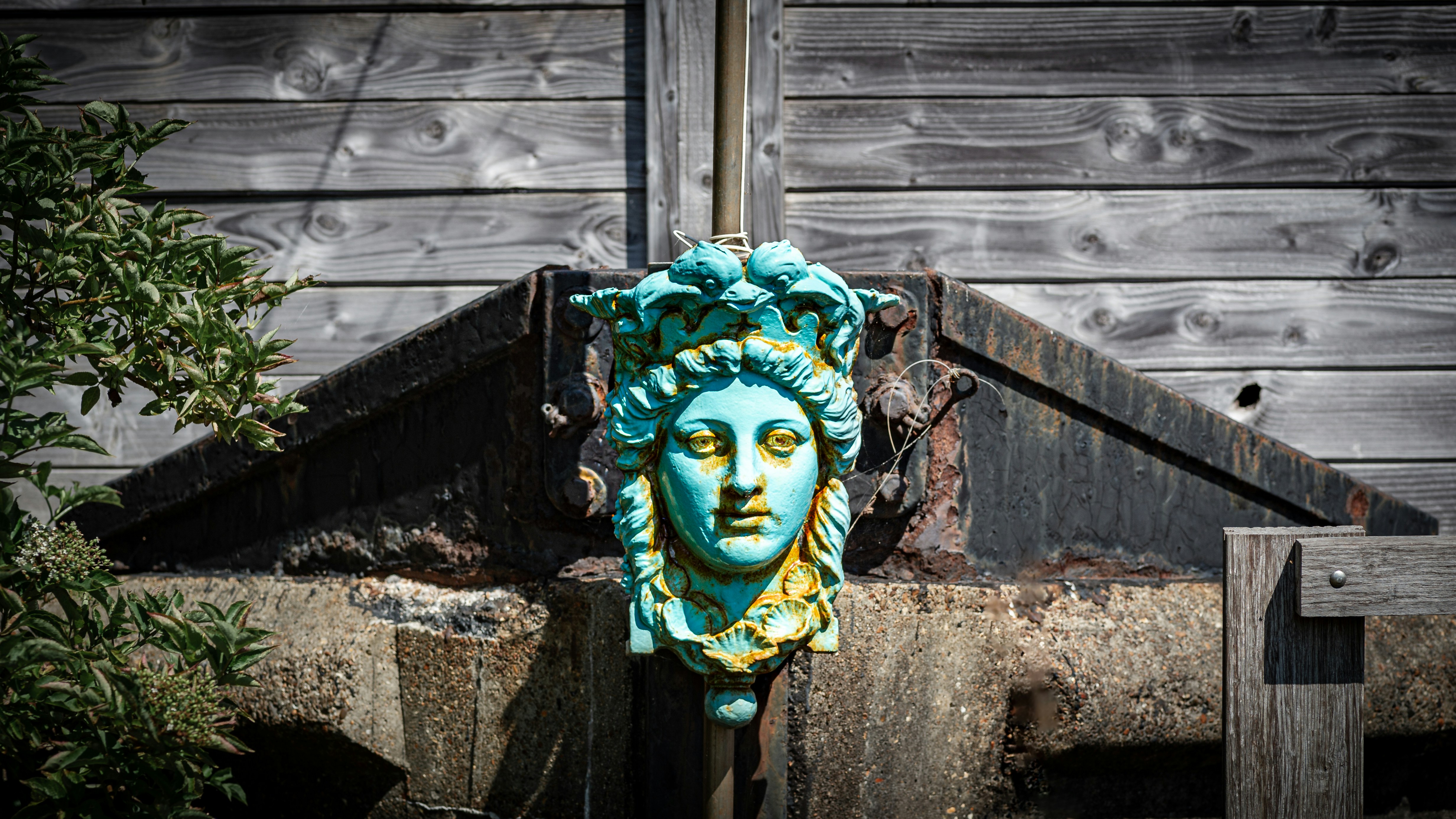 Patinaed Gorgon Head Anchored to a Weathered Concrete Ledge