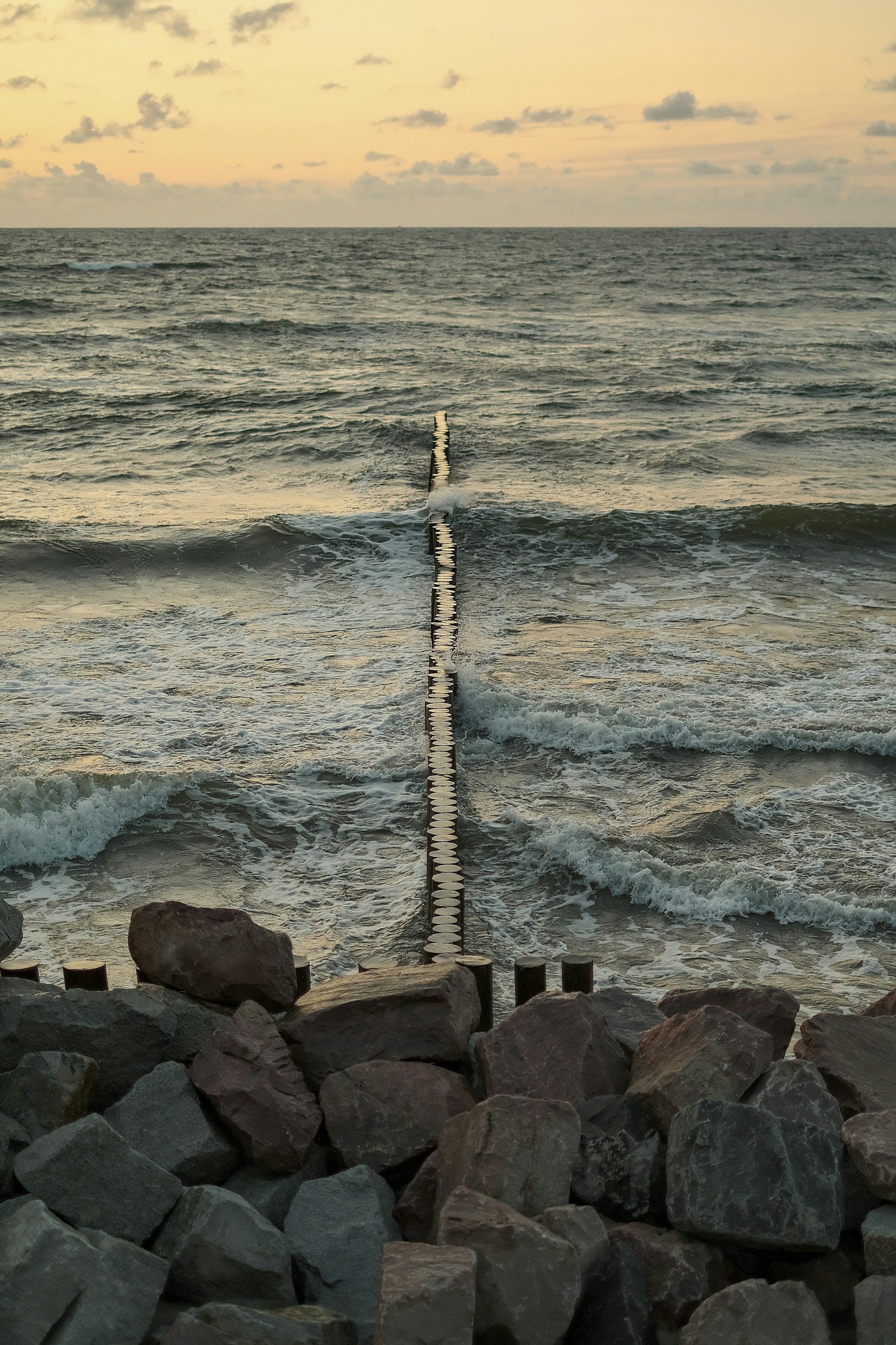 A long line of rocks sitting on top of a beach next to the ocean photo ...