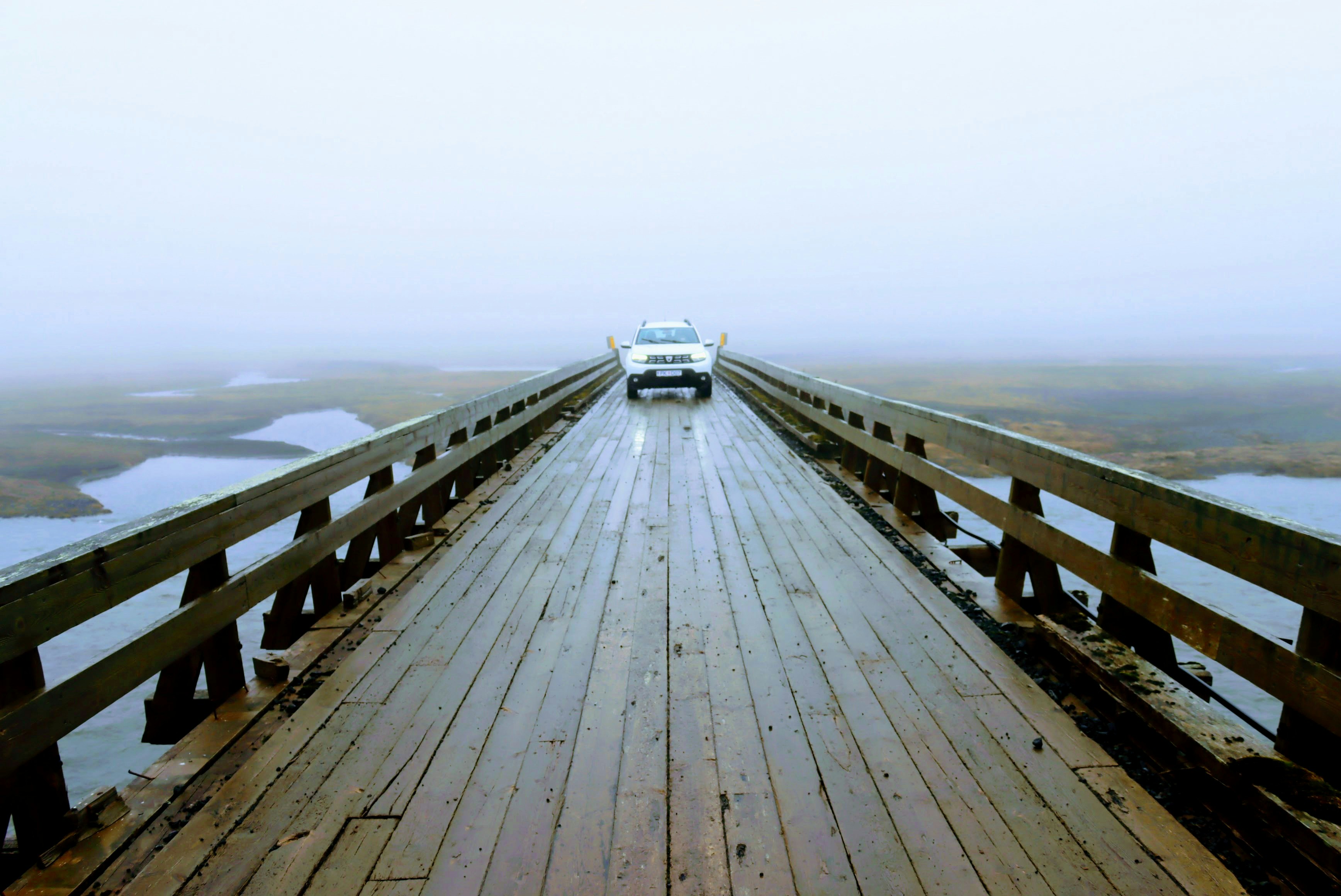 A car driving across a wooden bridge over a body of water photo – Free ...