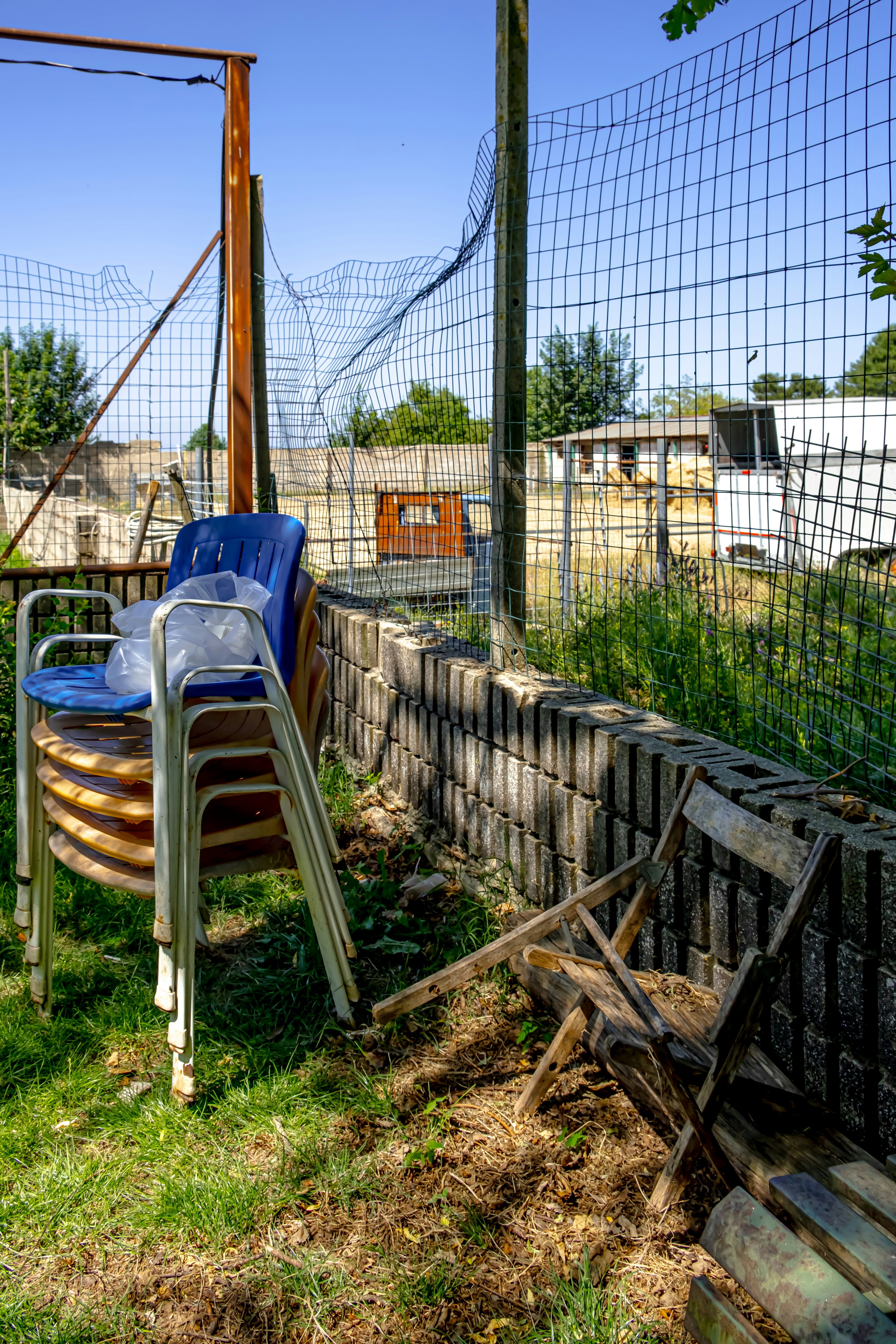 Blue Chairs in a Sunlit Yard Framed by Fence and Brick Wall