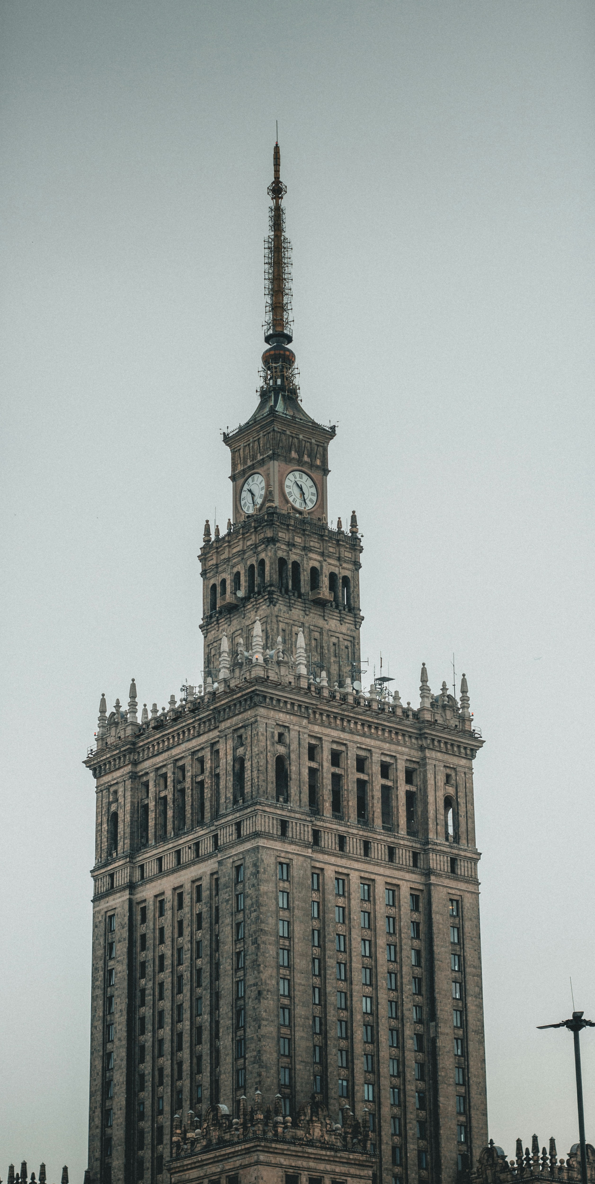 Historic skyscraper adorned with intricate details and clock faces, rising against a muted sky.