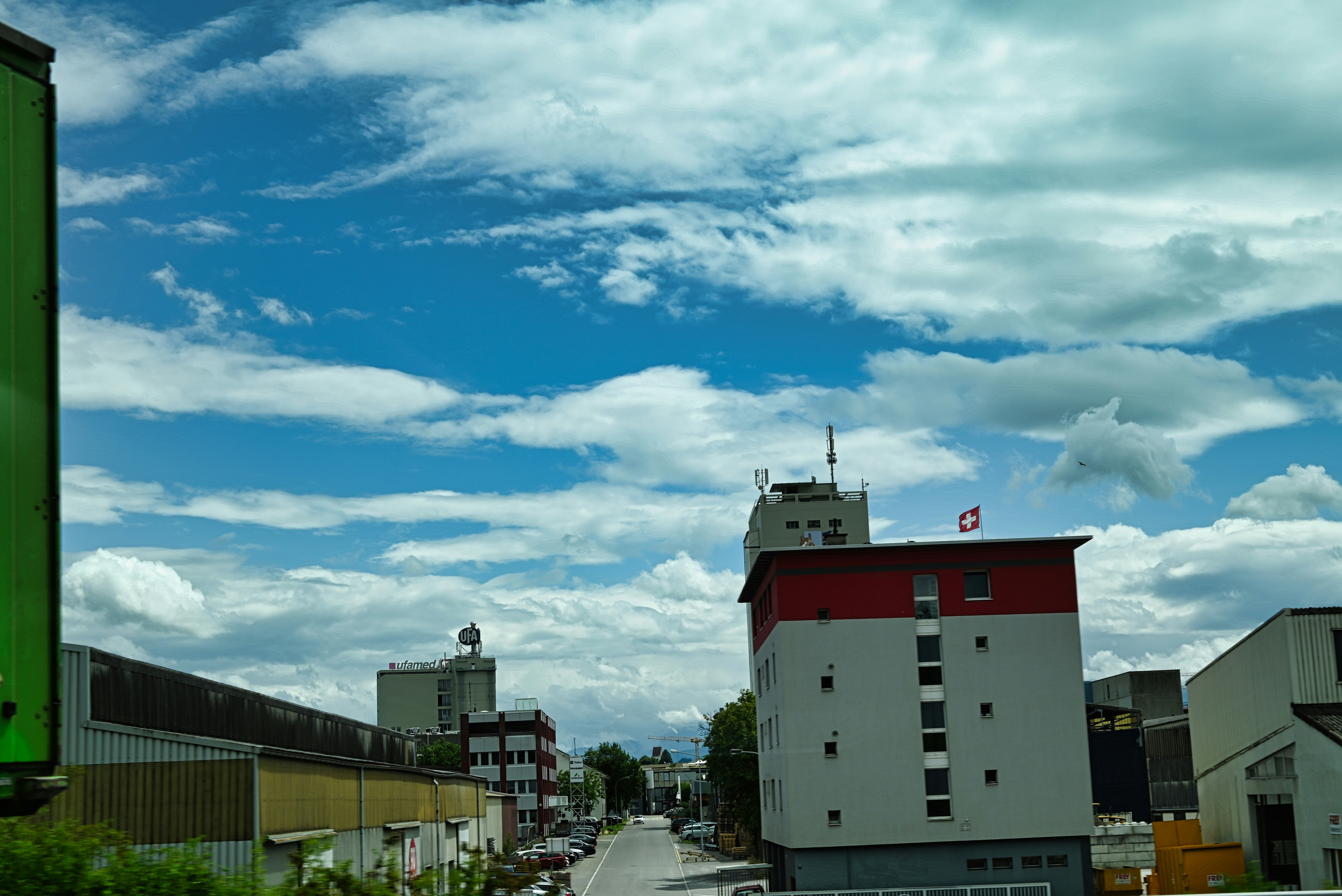 Flag-Topped Red-and-White Tower Anchors a Sunlit Industrial Street