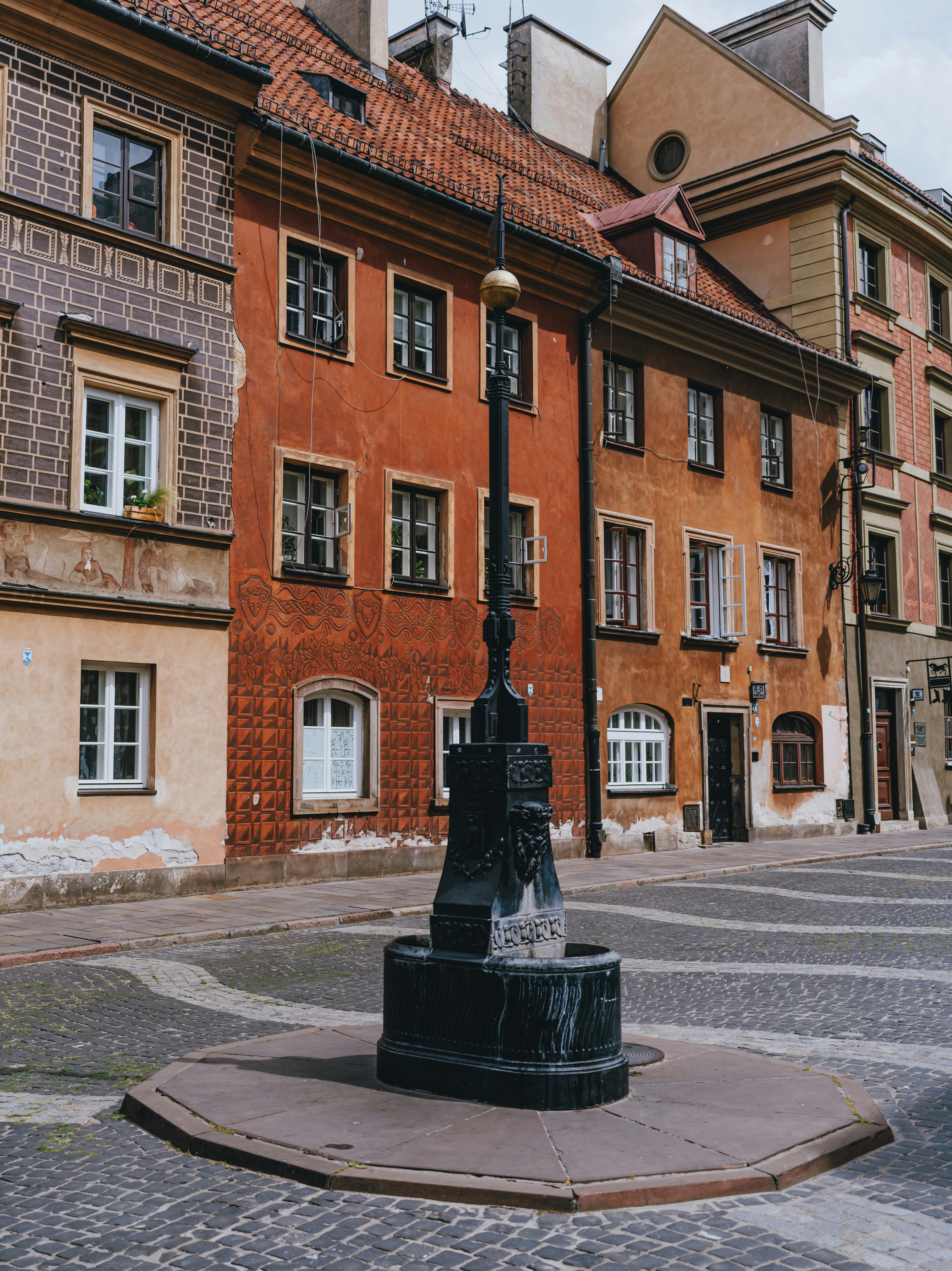 Centrepiece Lantern on a Circular Pedestal Among Painted Townhouses