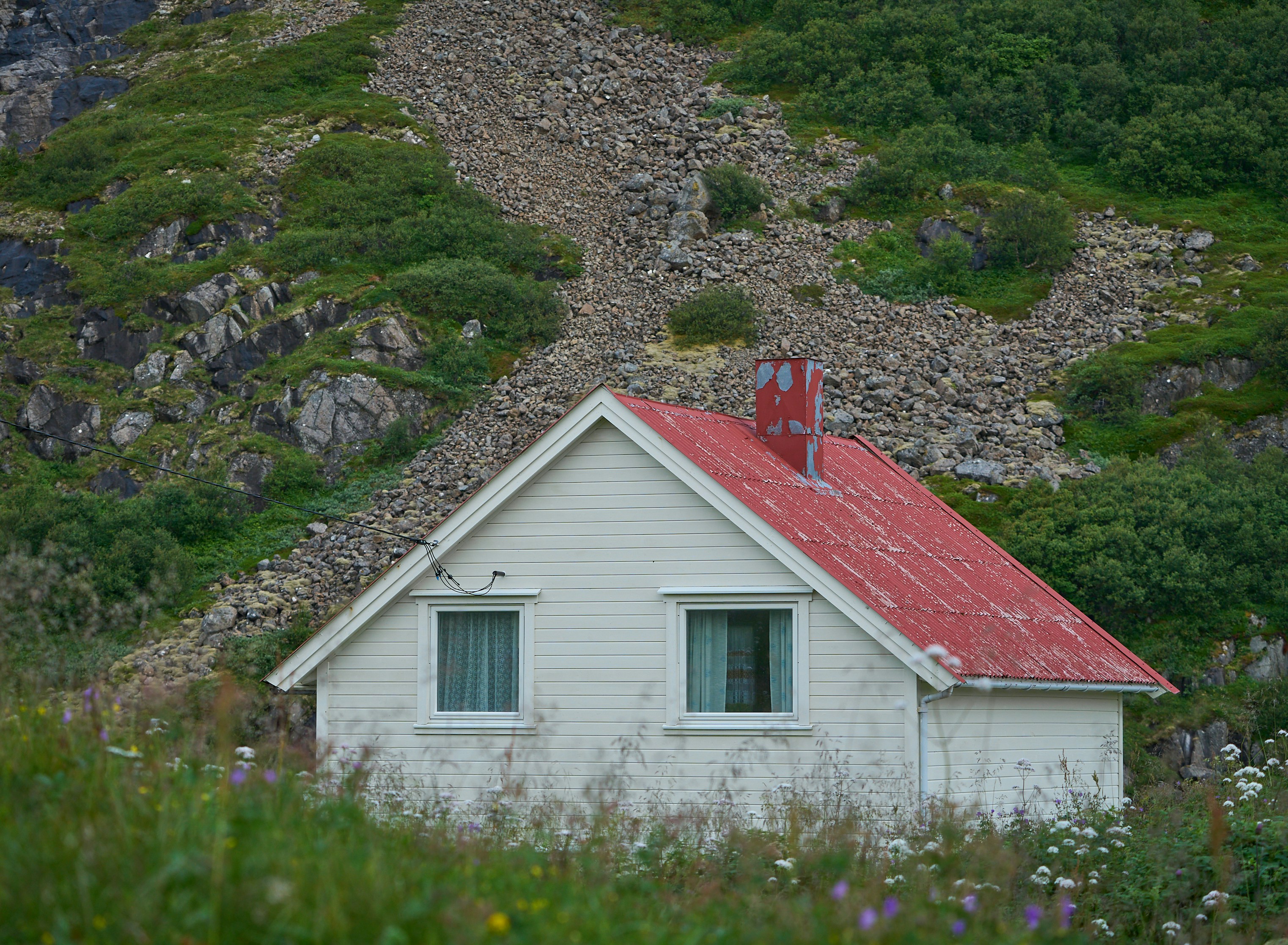 Red-roofed Cottage Nestled Along a Rugged Hillside