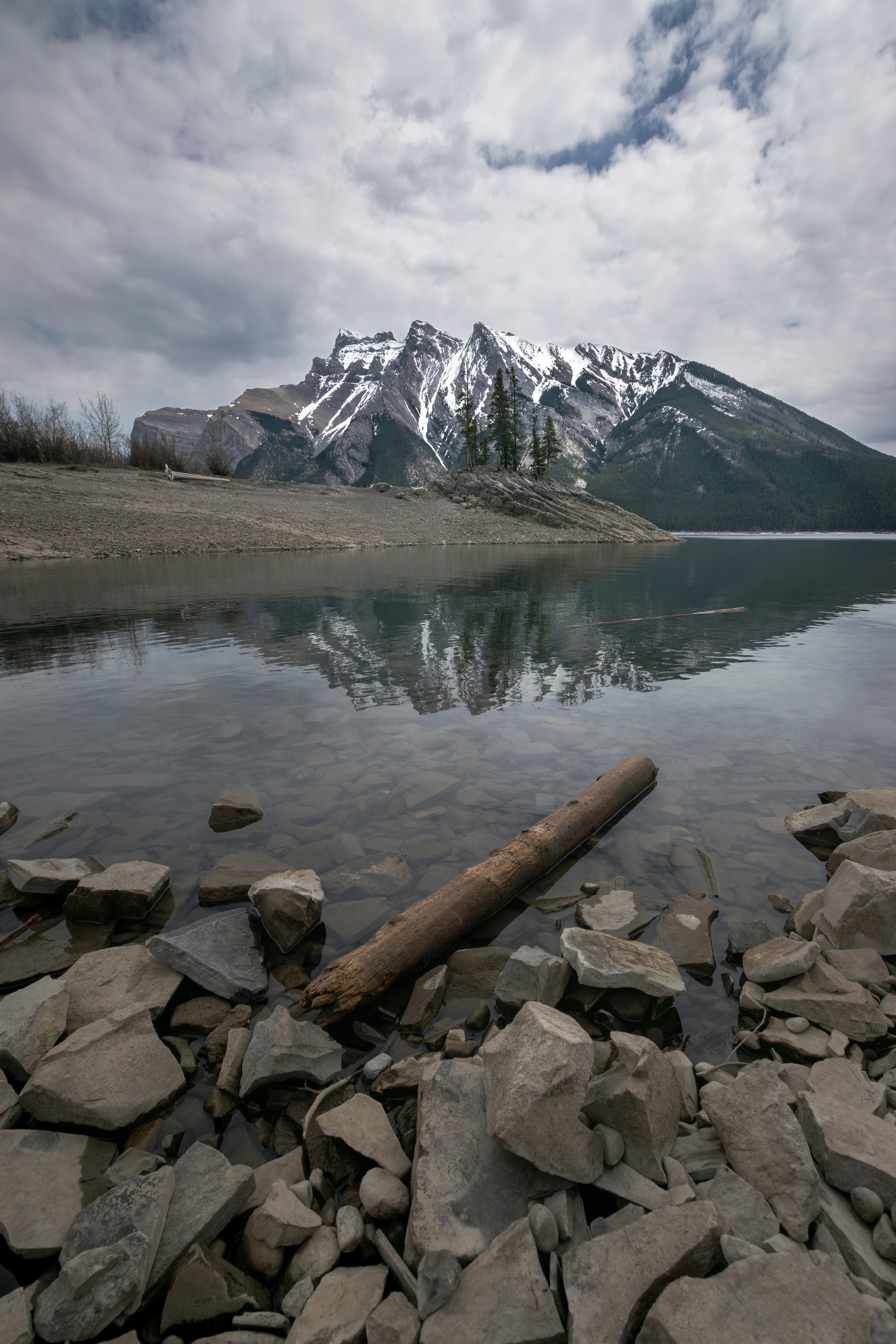 Snow‑capped peak reflected in a tranquil alpine lake beneath a stormy sky