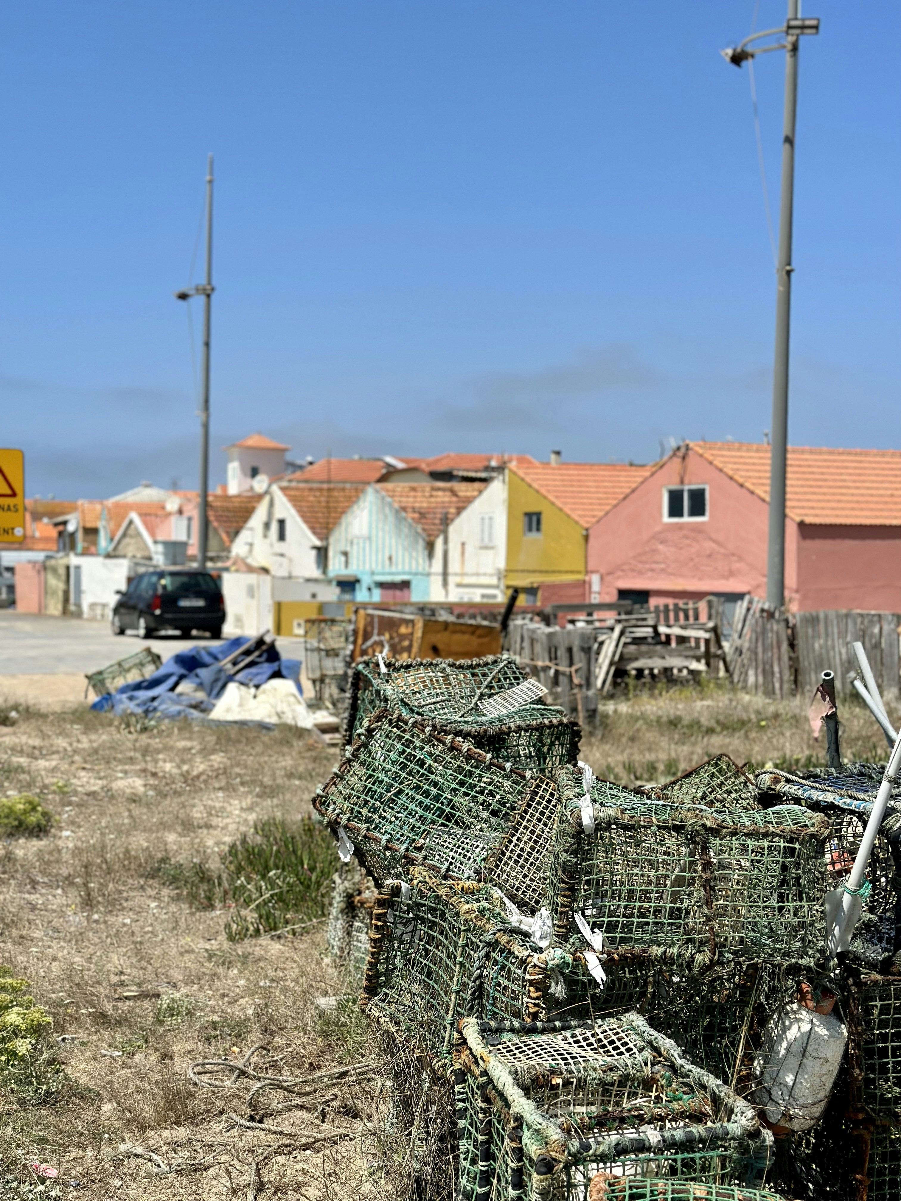 Pastel Wharf: Foreground Crates, Distant Row of Colorful Cottages