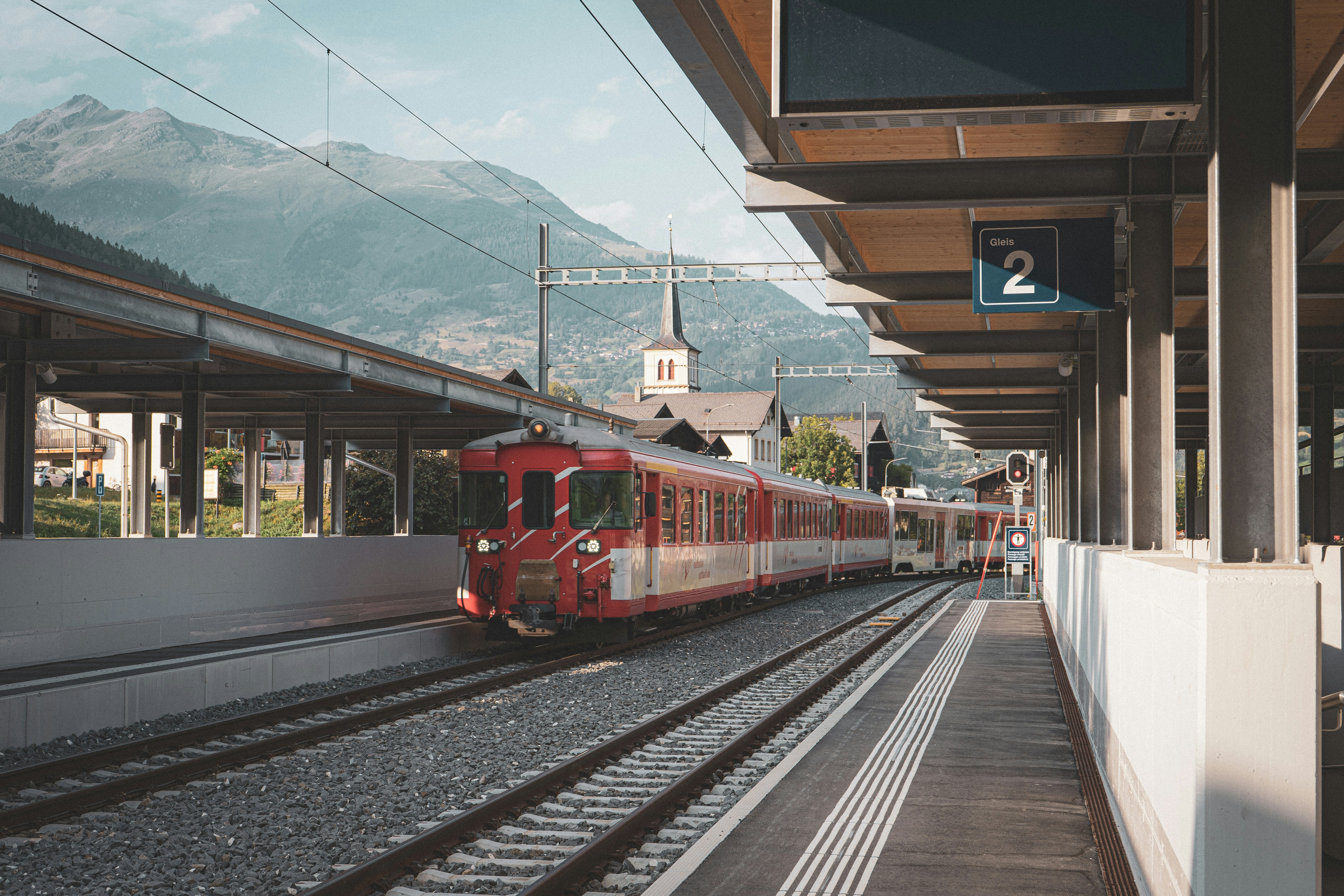 A red and white train pulling into a train station photo – Free ...