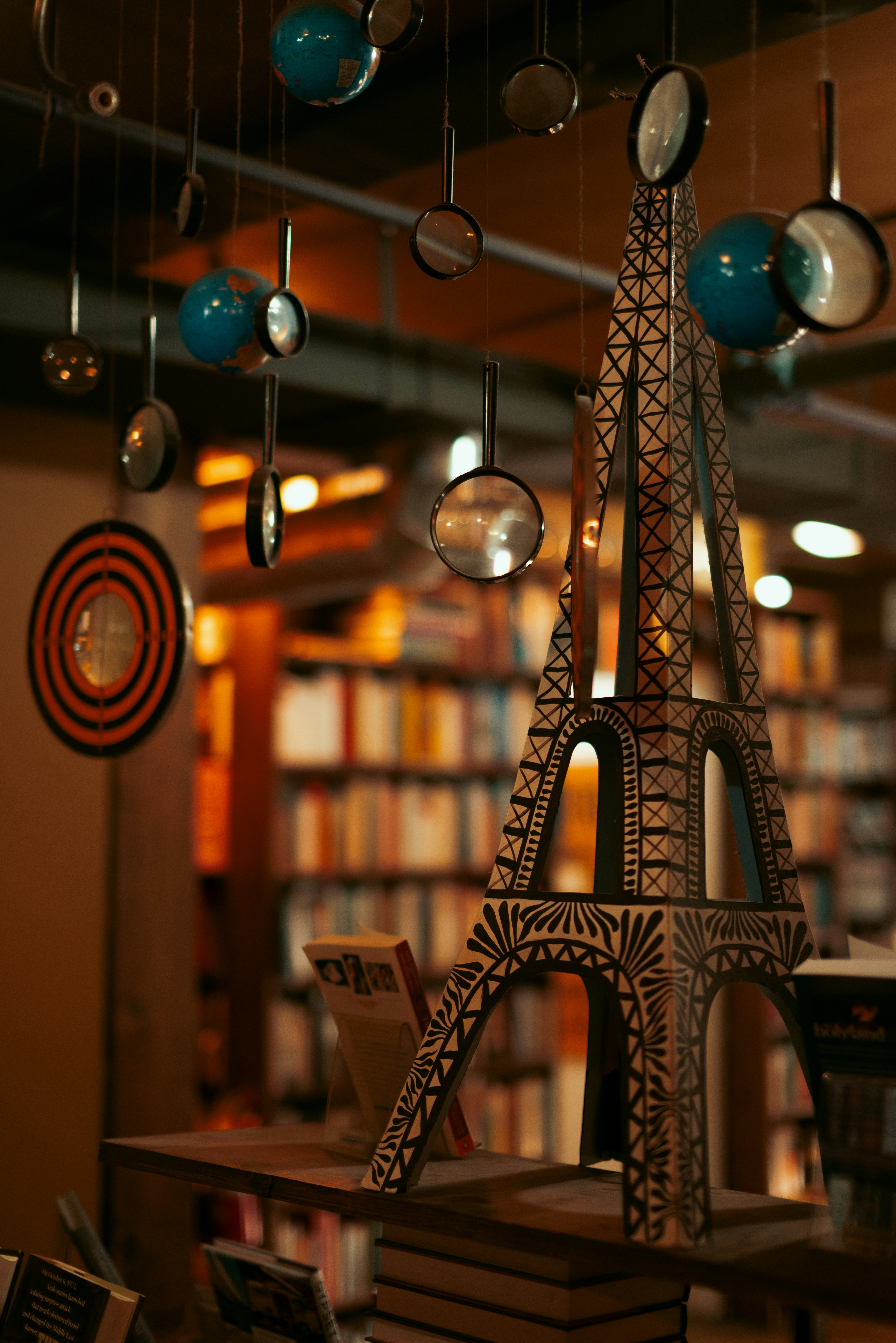 Lattice under Lanterns: A miniature Eiffel Tower among suspended globes in a cozy bookstore
