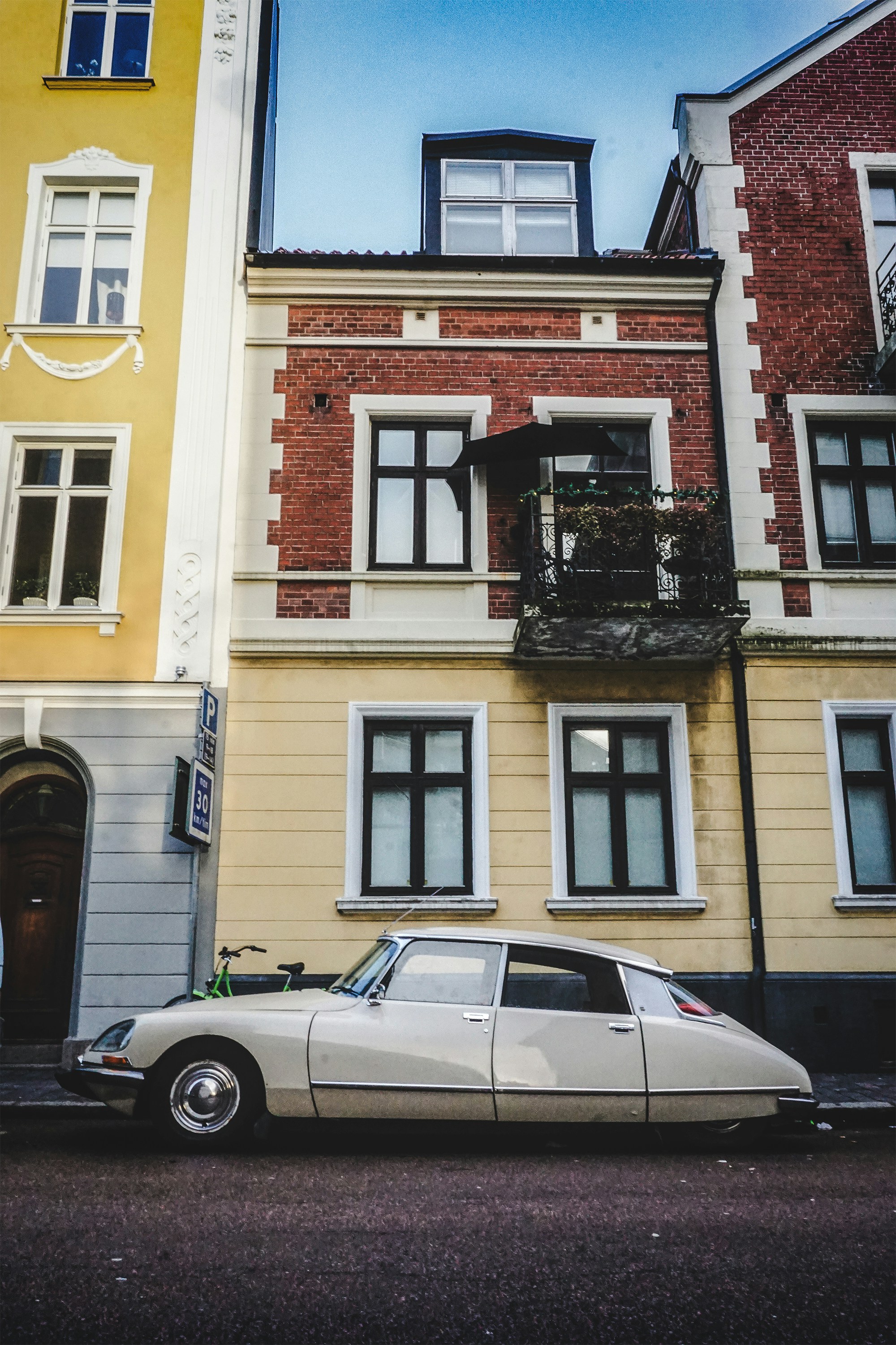Vintage sedan on a sunlit European street framed by pastel facades and brick