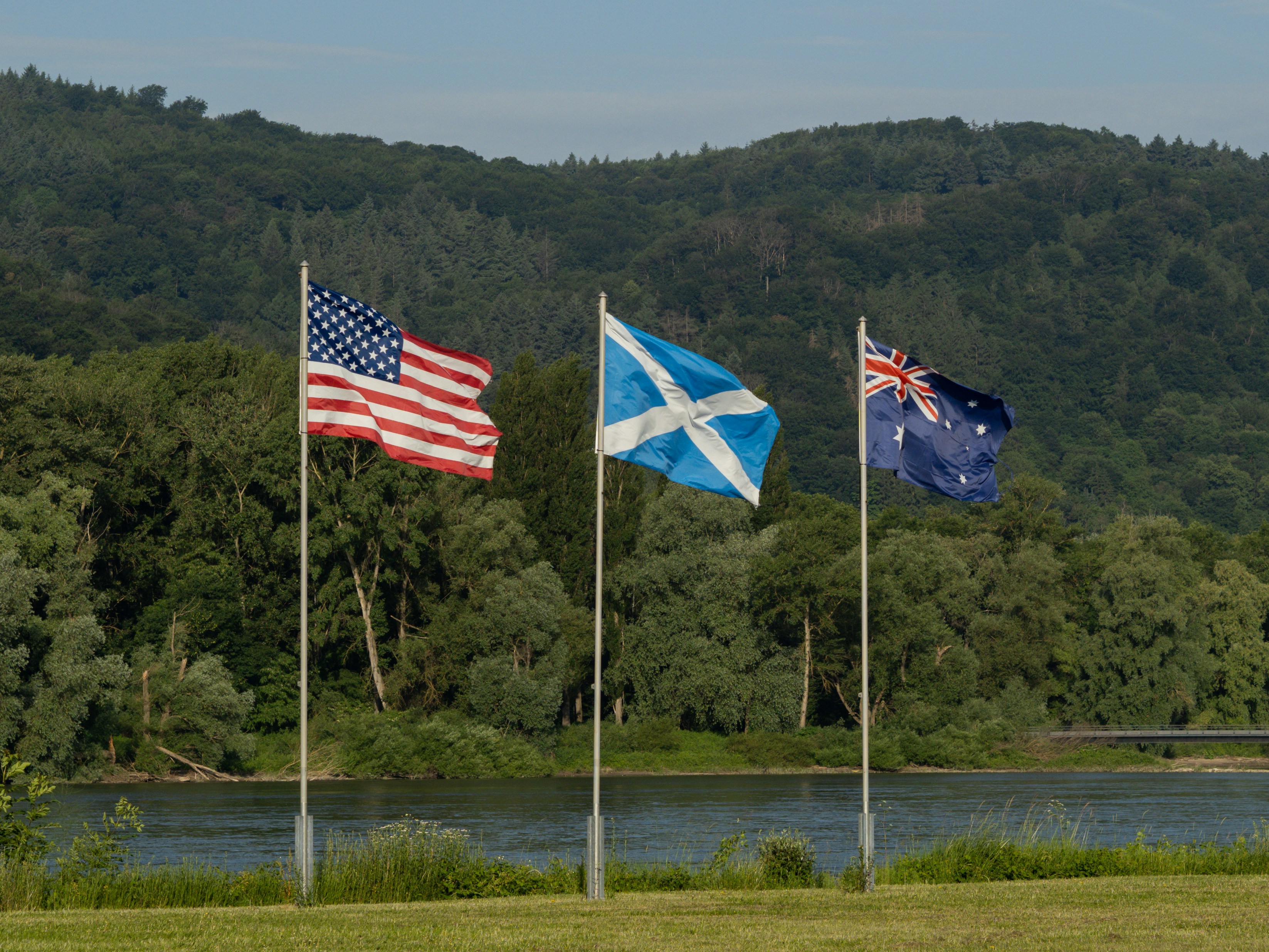 A group of three flags flying next to a river photo – Free Image on ...