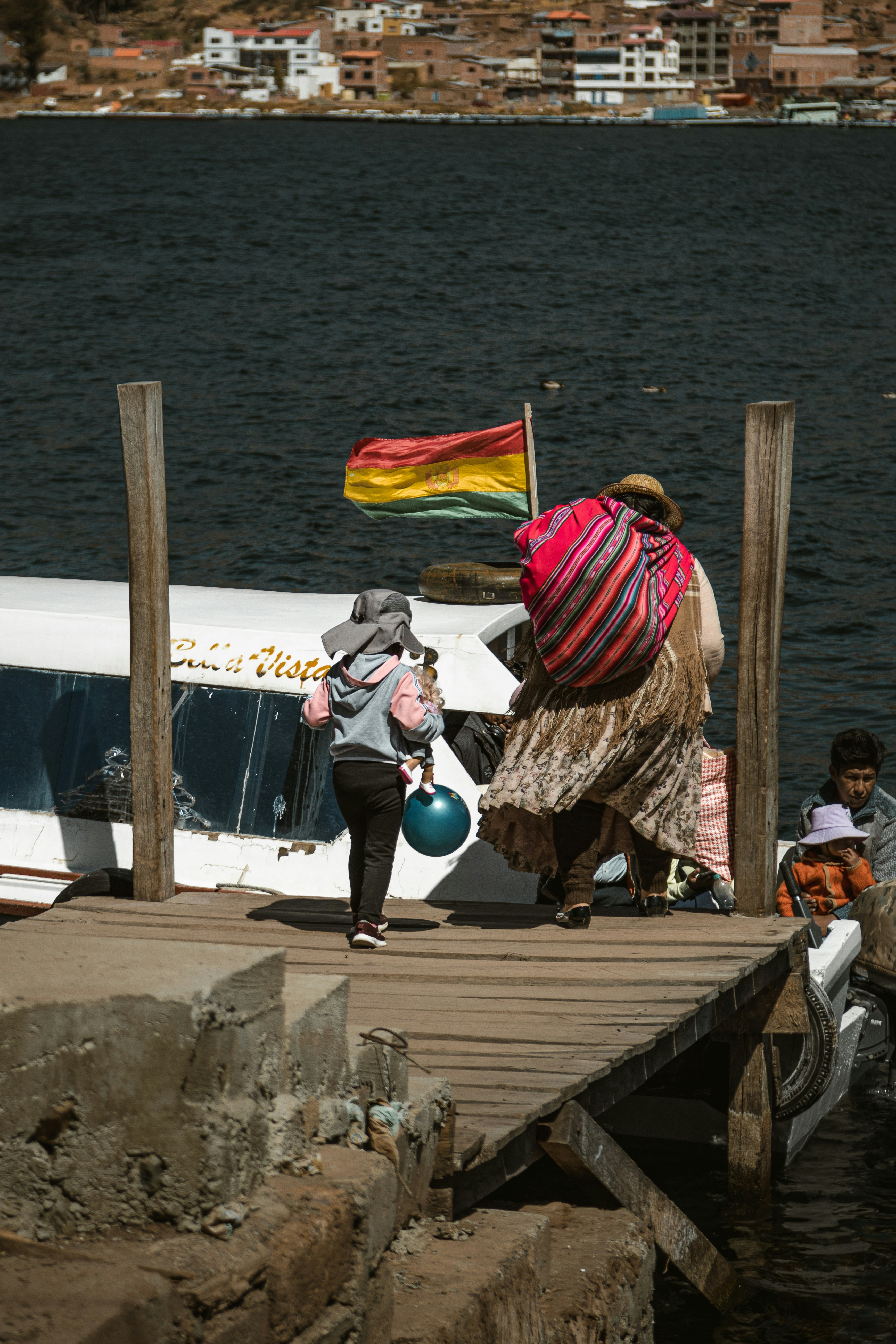A group of people standing on a dock next to a body of water photo ...