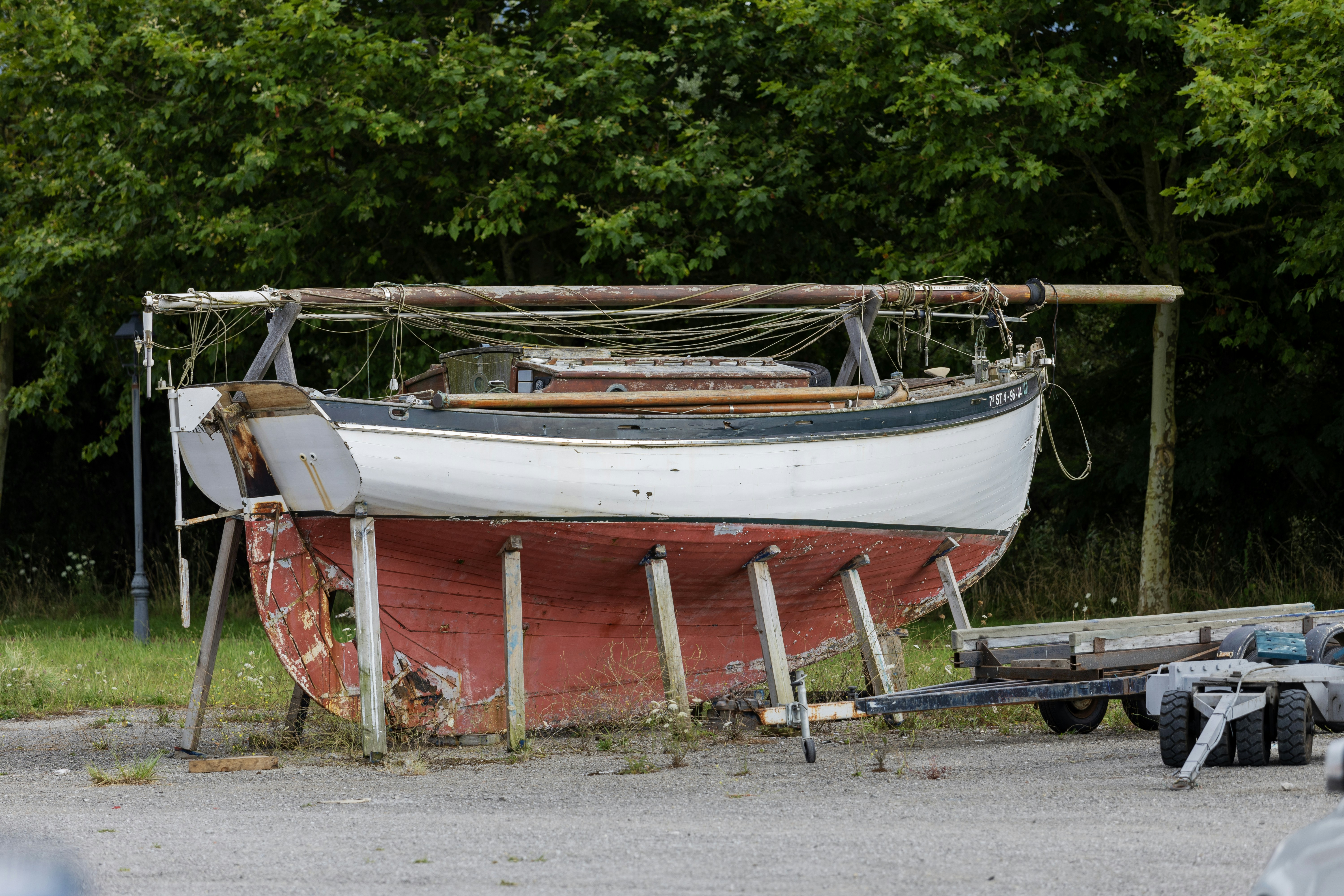 A boat sitting on the ground next to a trailer photo – Free Vehicle ...