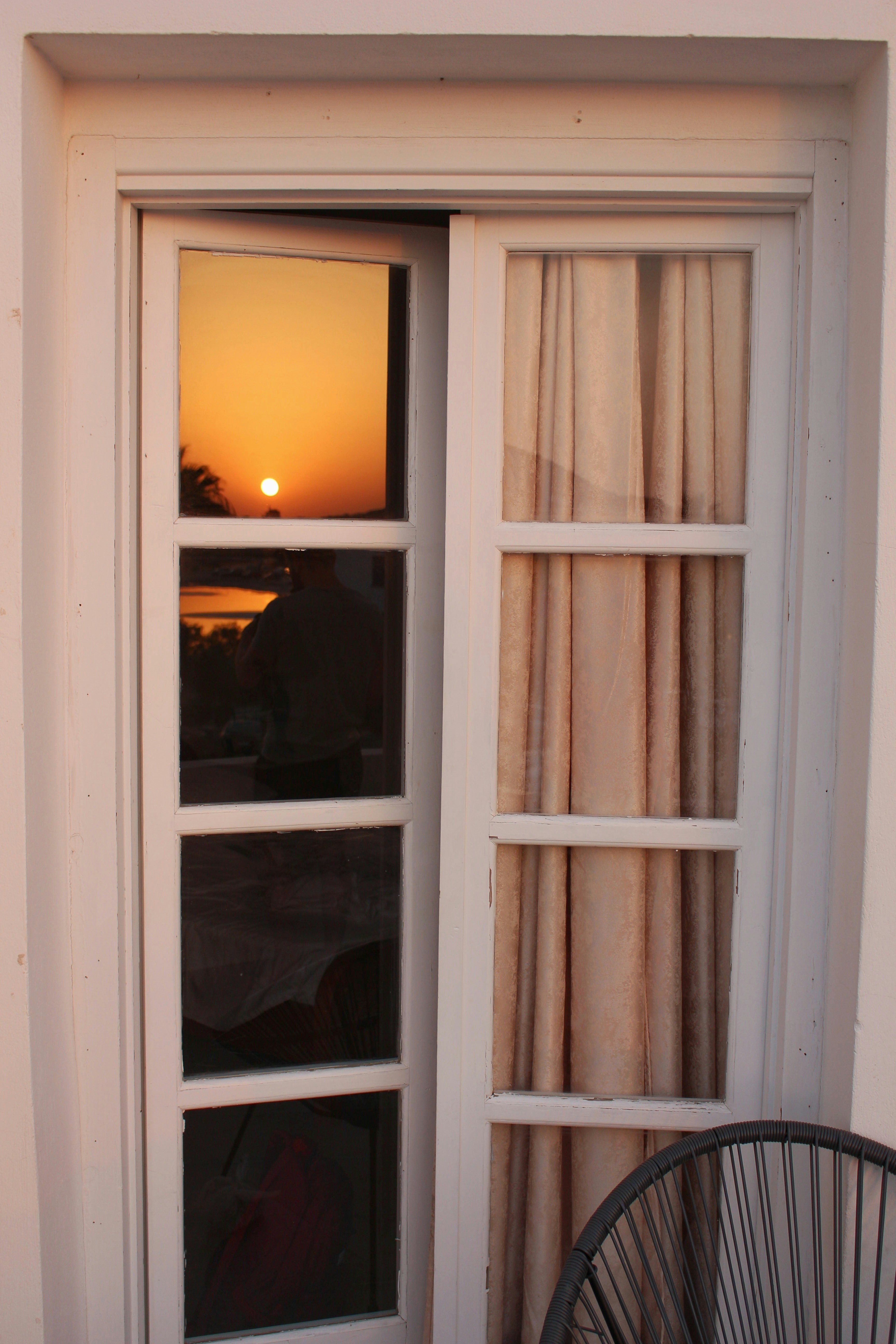 Sunlit Pane: Sunset Reflections in a White-Framed Door with Curtains