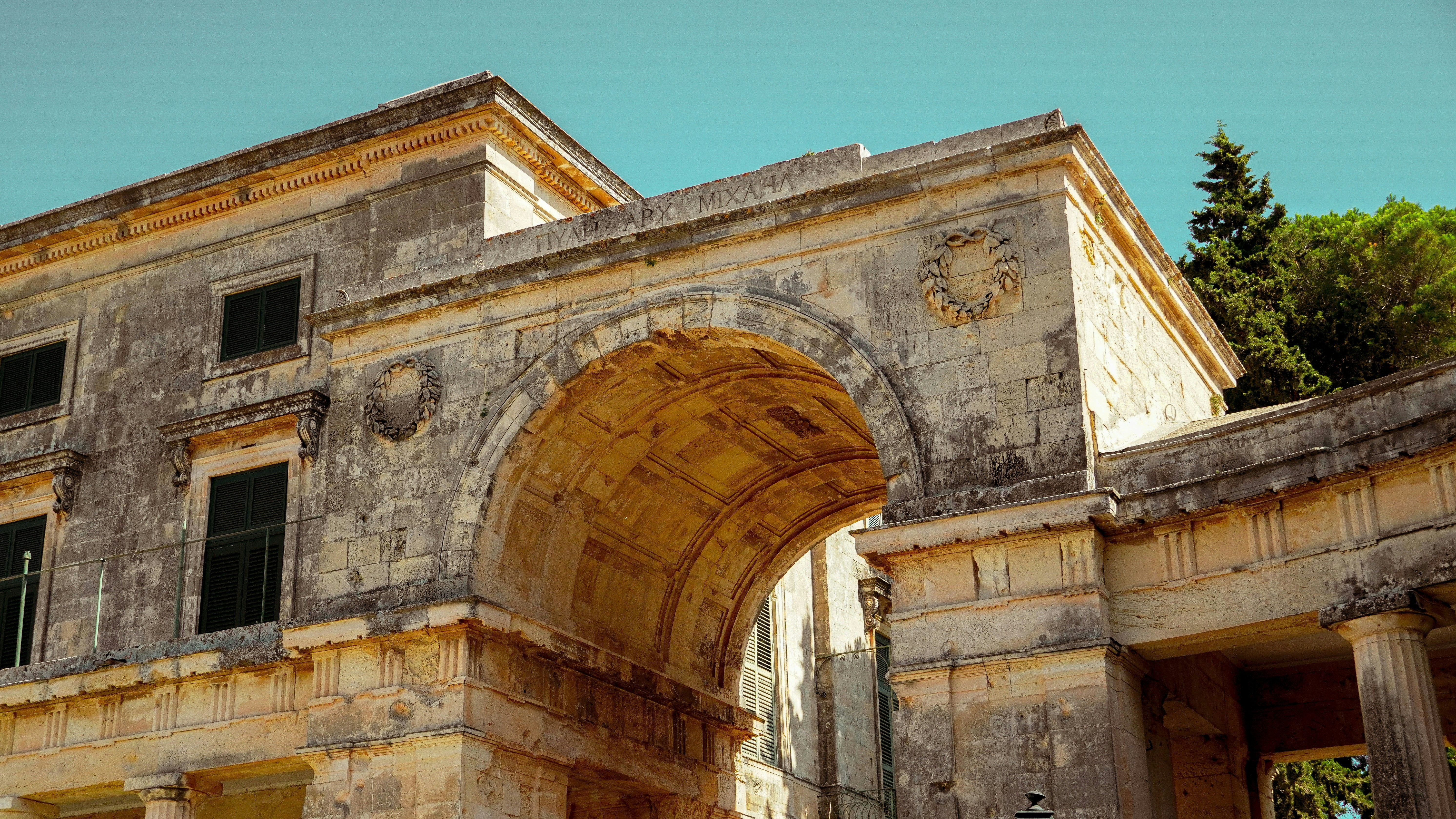 Sunlit Archway of Weathered Stone Against a Teal Sky