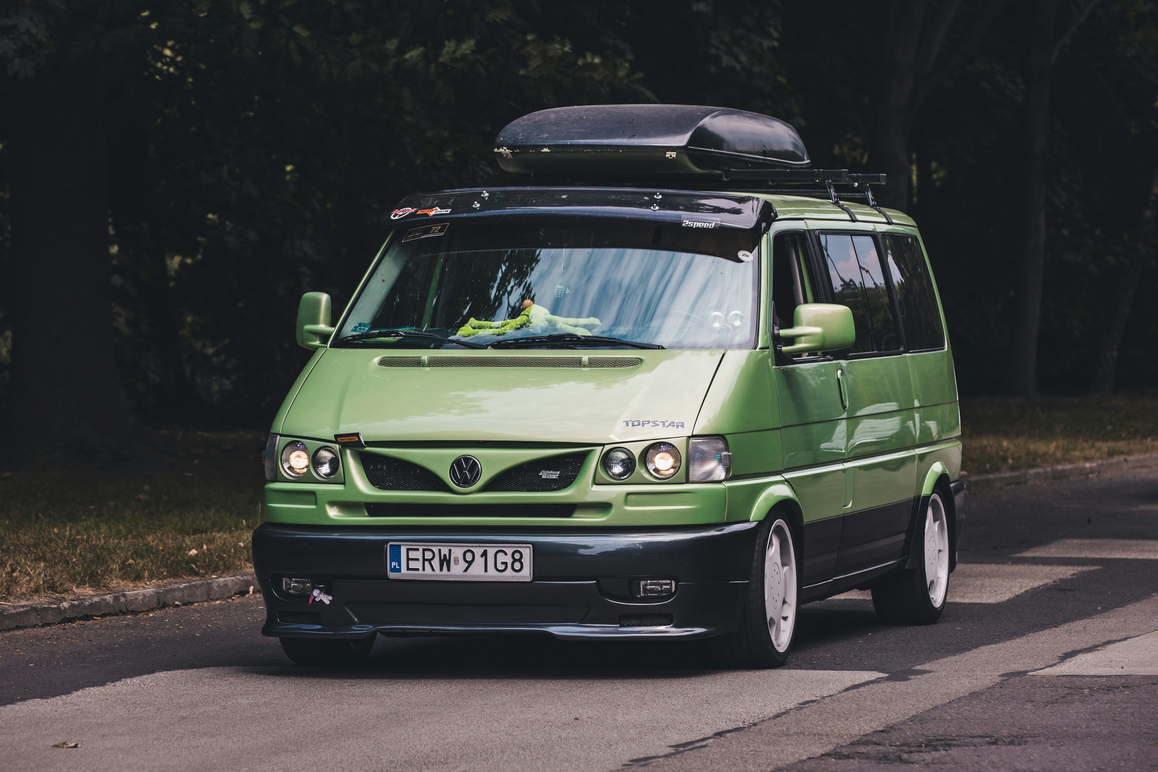 Emerald Volkswagen Transporter on a Quiet Suburban Street, Rooftop Gear in View