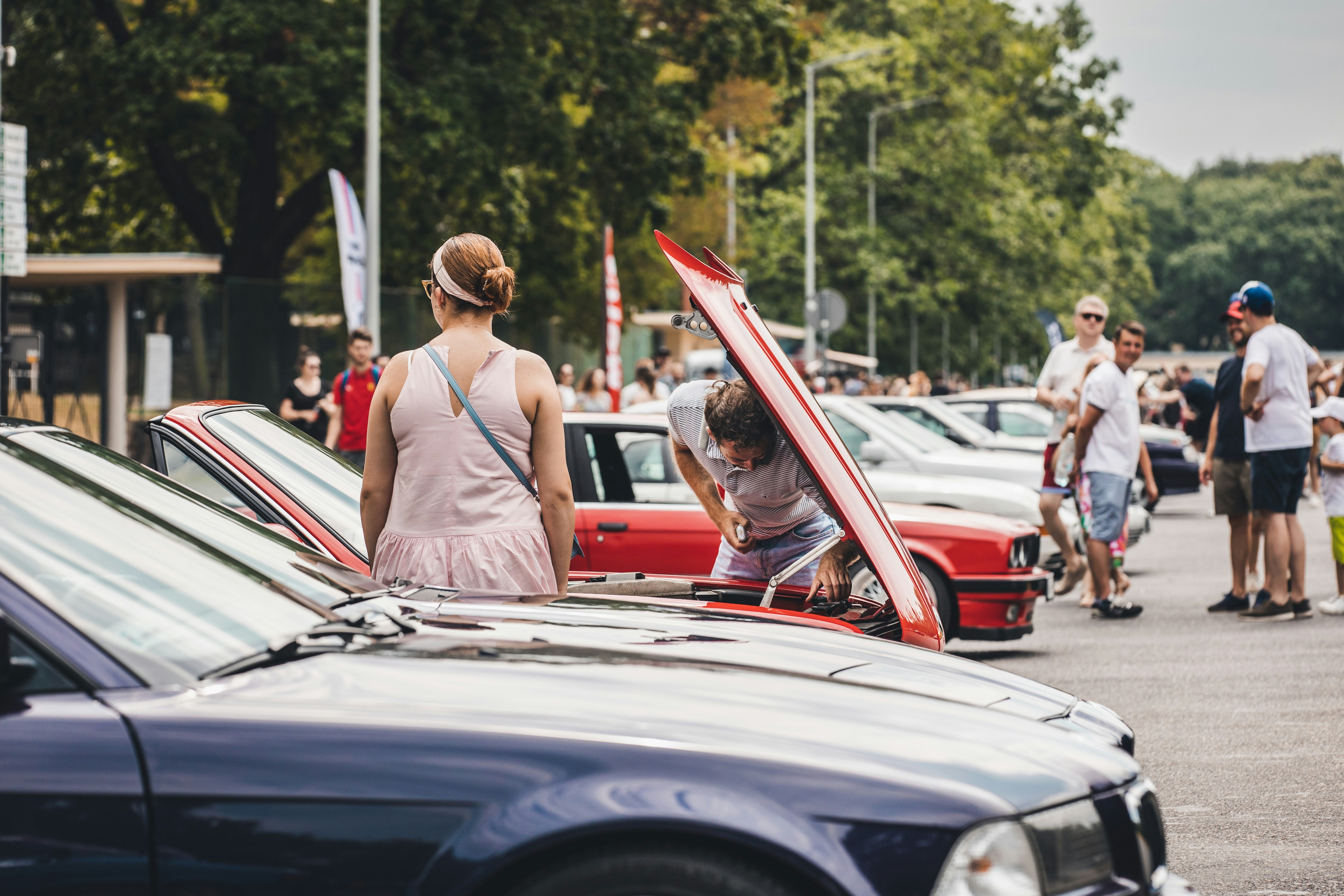 a group of people standing around parked cars